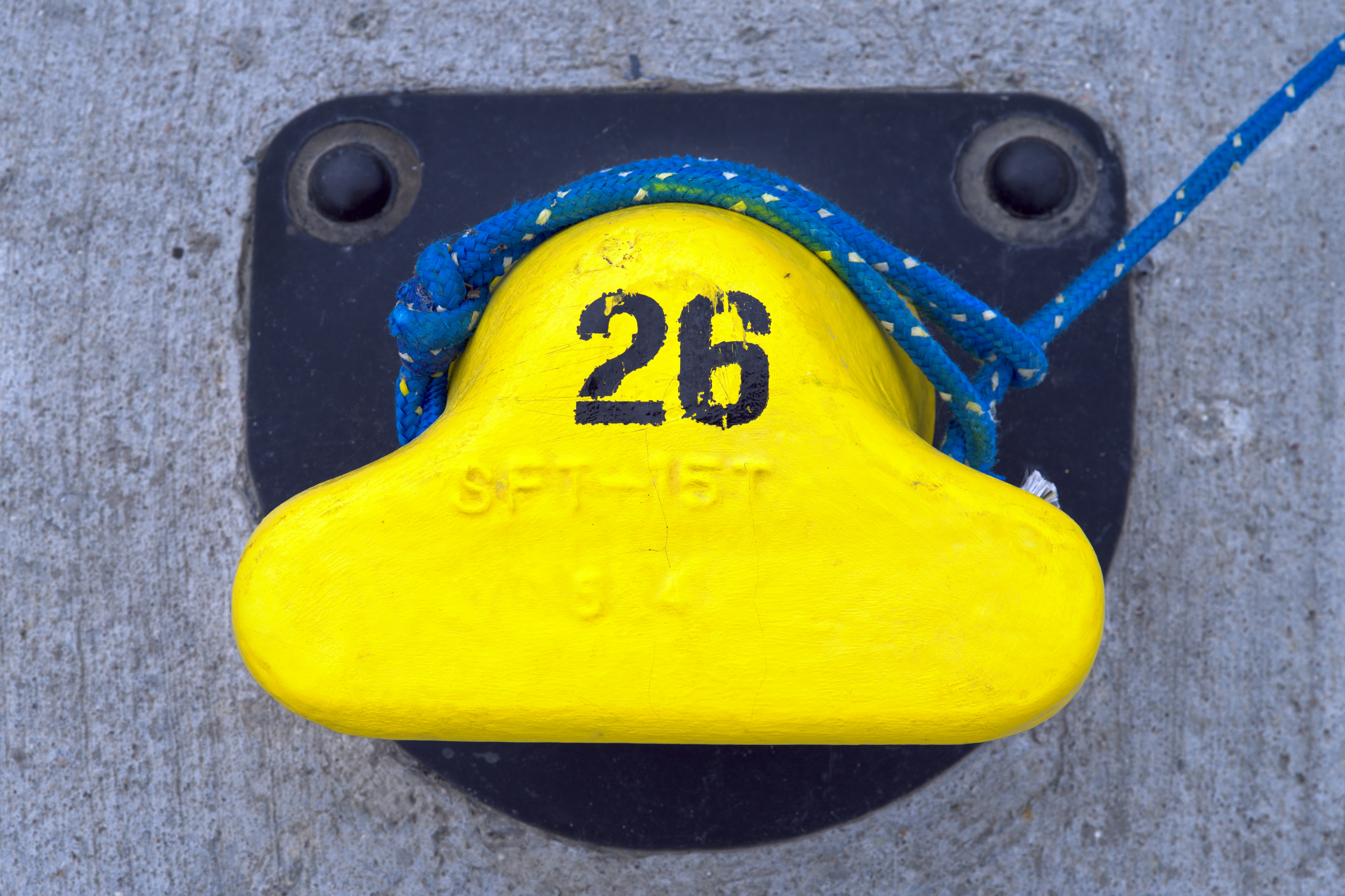 Yellow bollard with rope on a concrete dock
