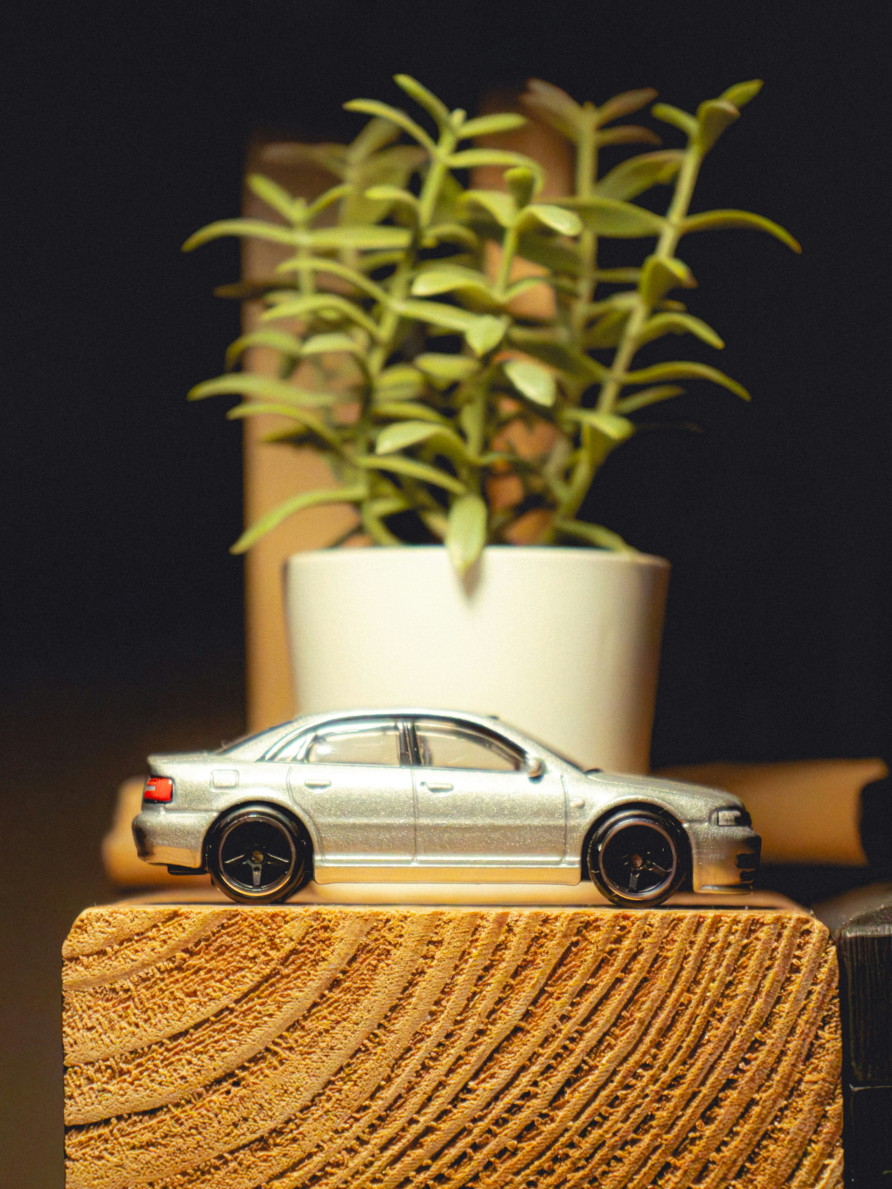 Miniature Silver Sedan Anchored on a Wooden Block