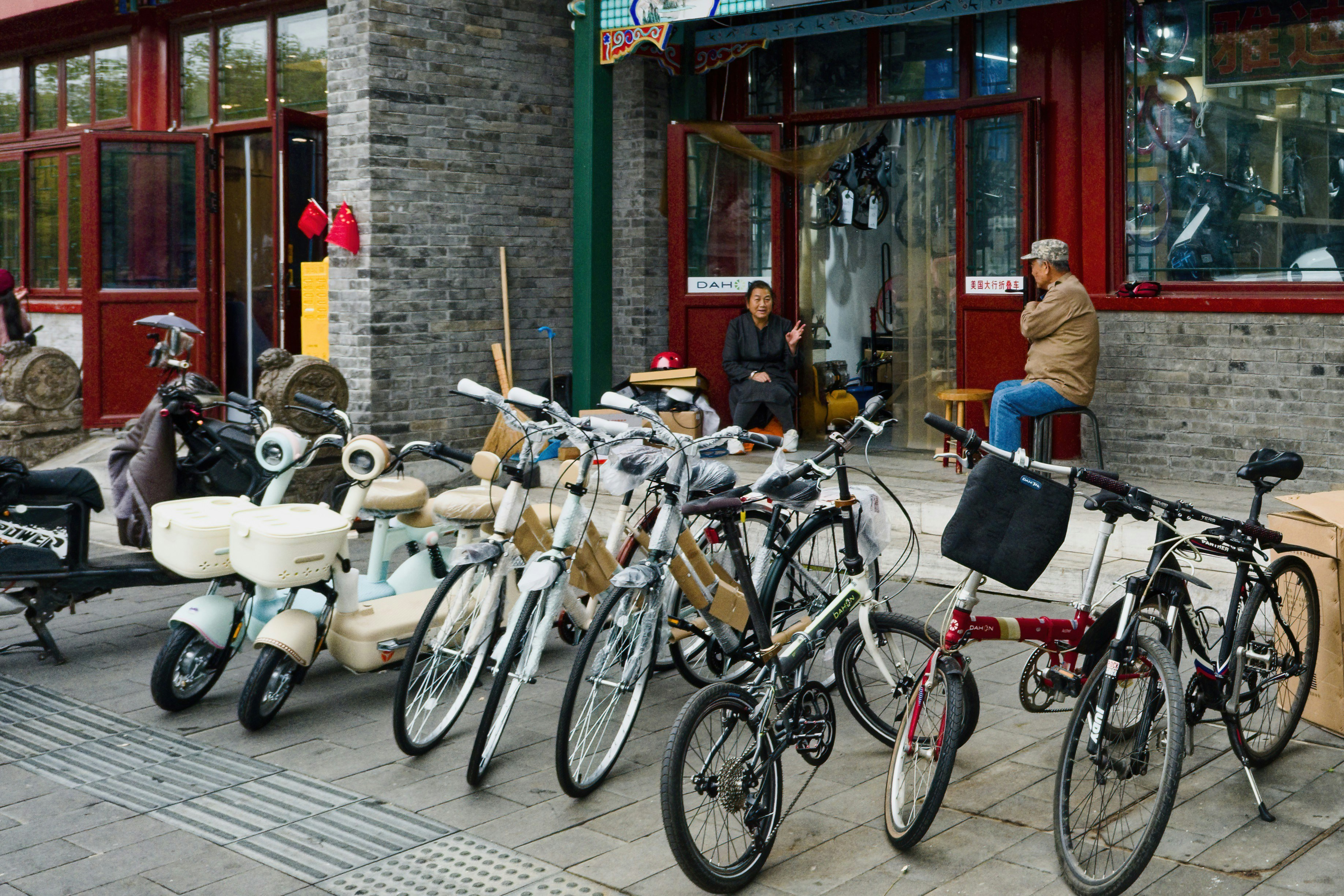 Bikes and scooters lined up on a busy storefront street