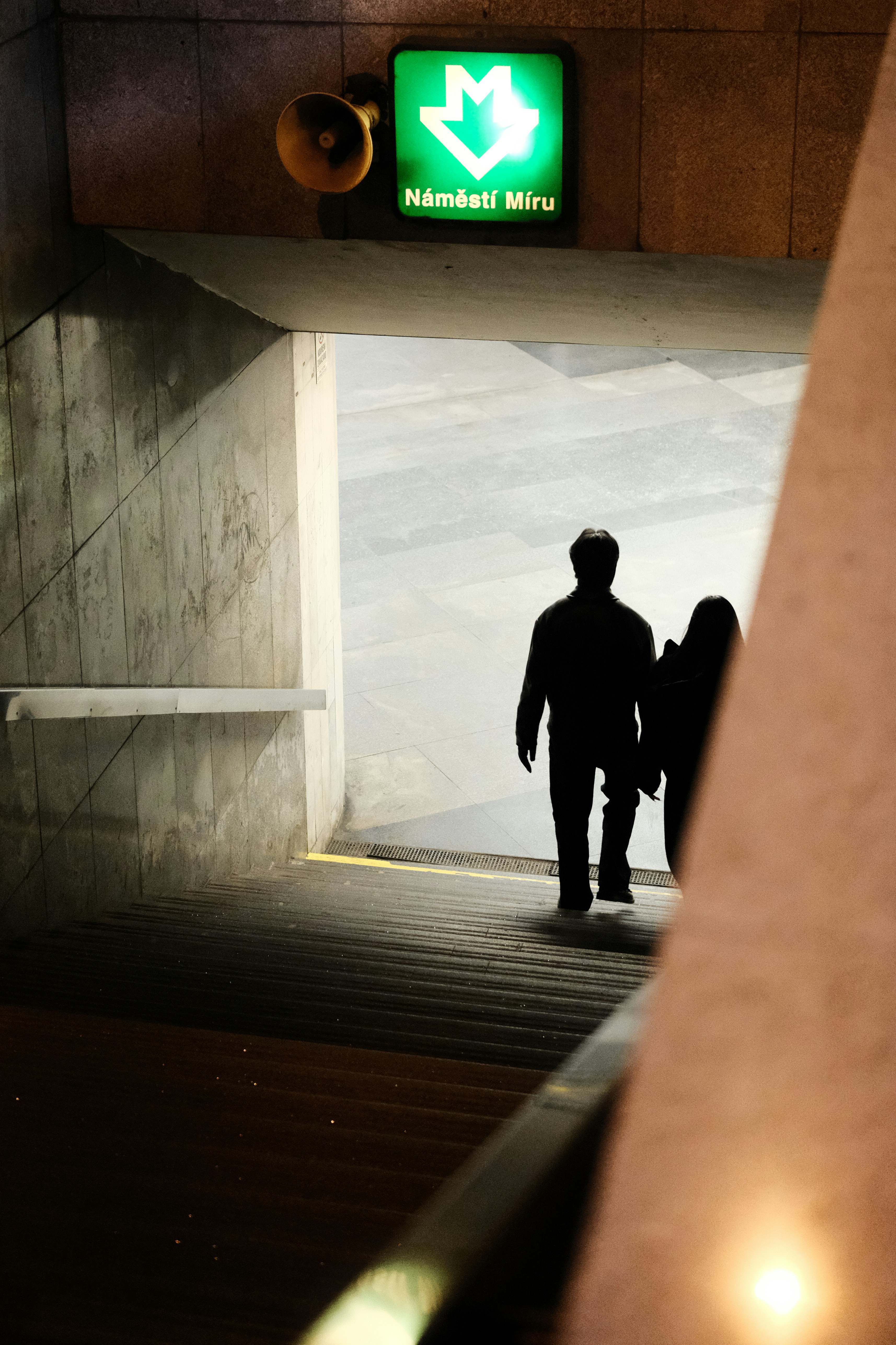 Shadowed Ascent: Two Figures Haunting the Subway Threshold