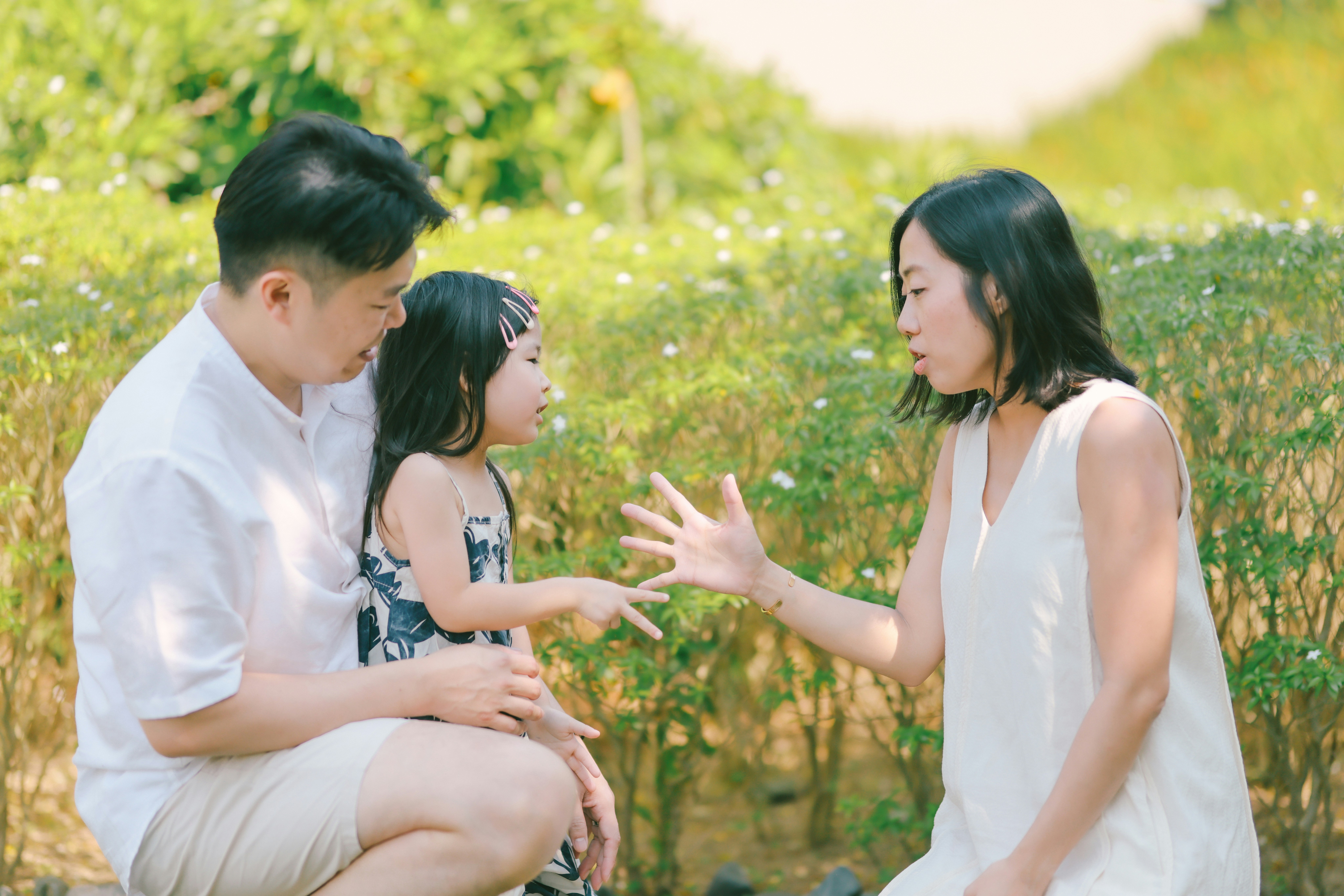 Conversation in the Golden Garden: Father and Daughter Share a Moment with Mother Approaching