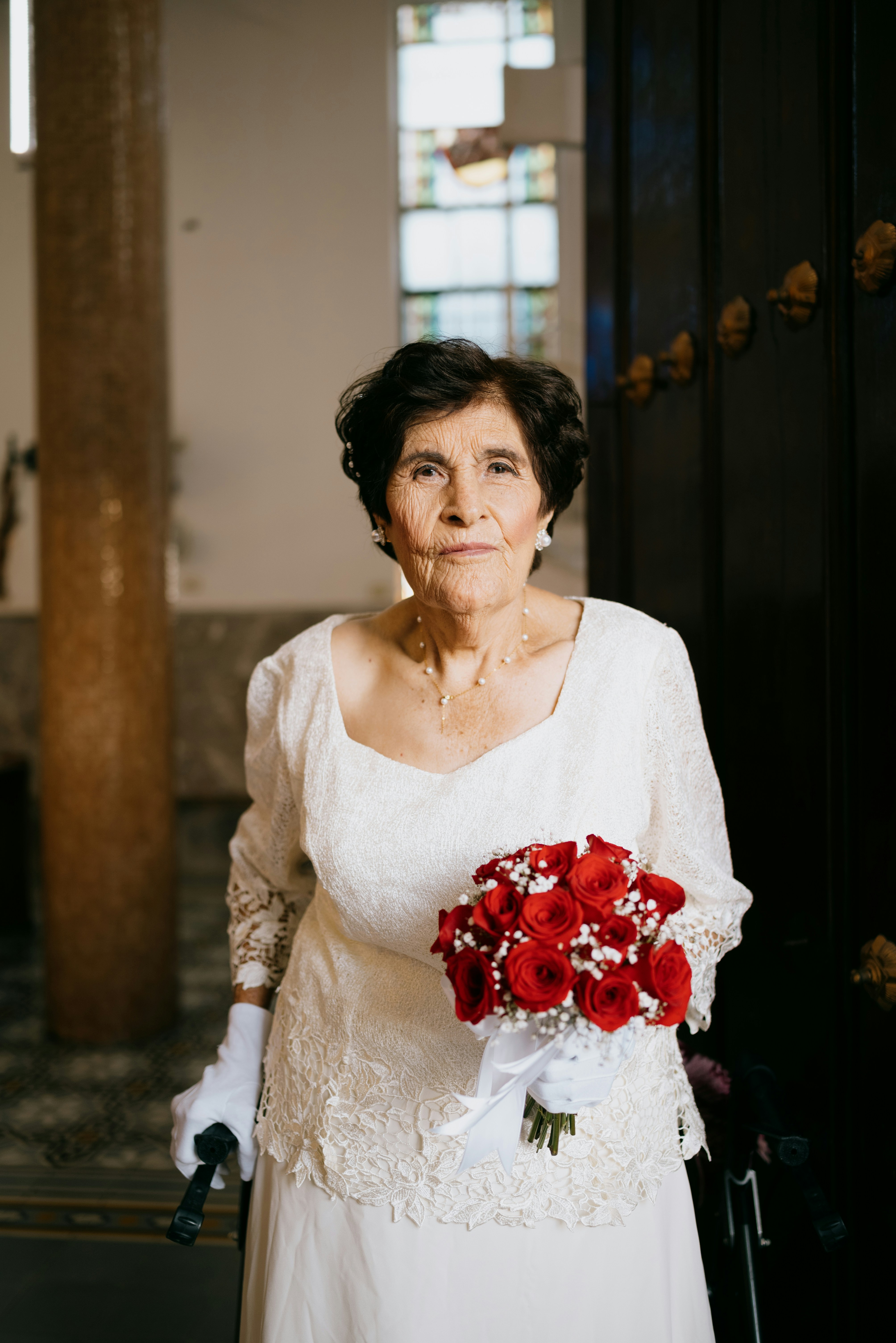 Bride in White: A Gentle Portrait of Grace with a Crimson Bouquet