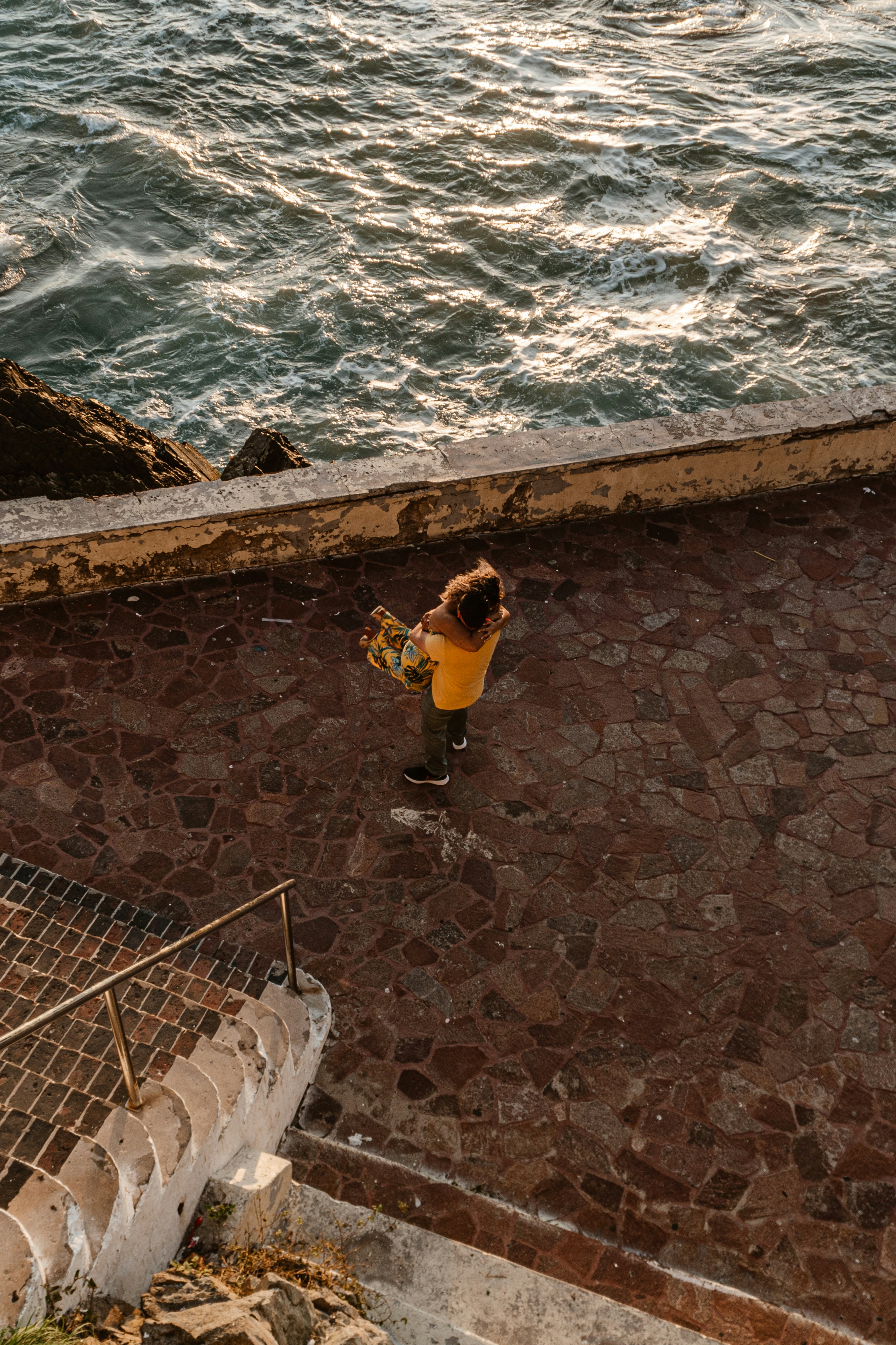 Top-Down Moment: Child in yellow by the sea wall