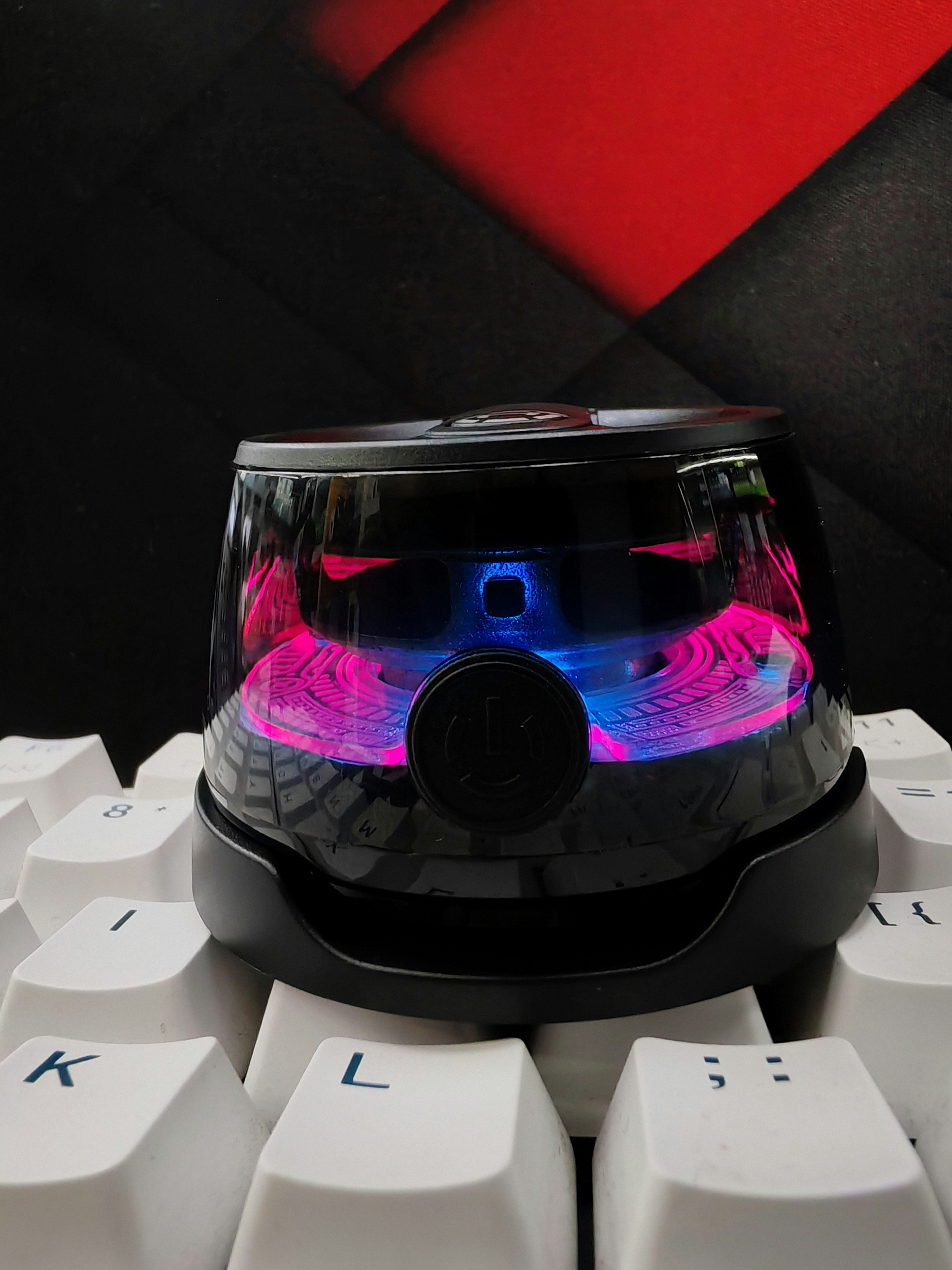 A black speaker with colorful lights on a keyboard.