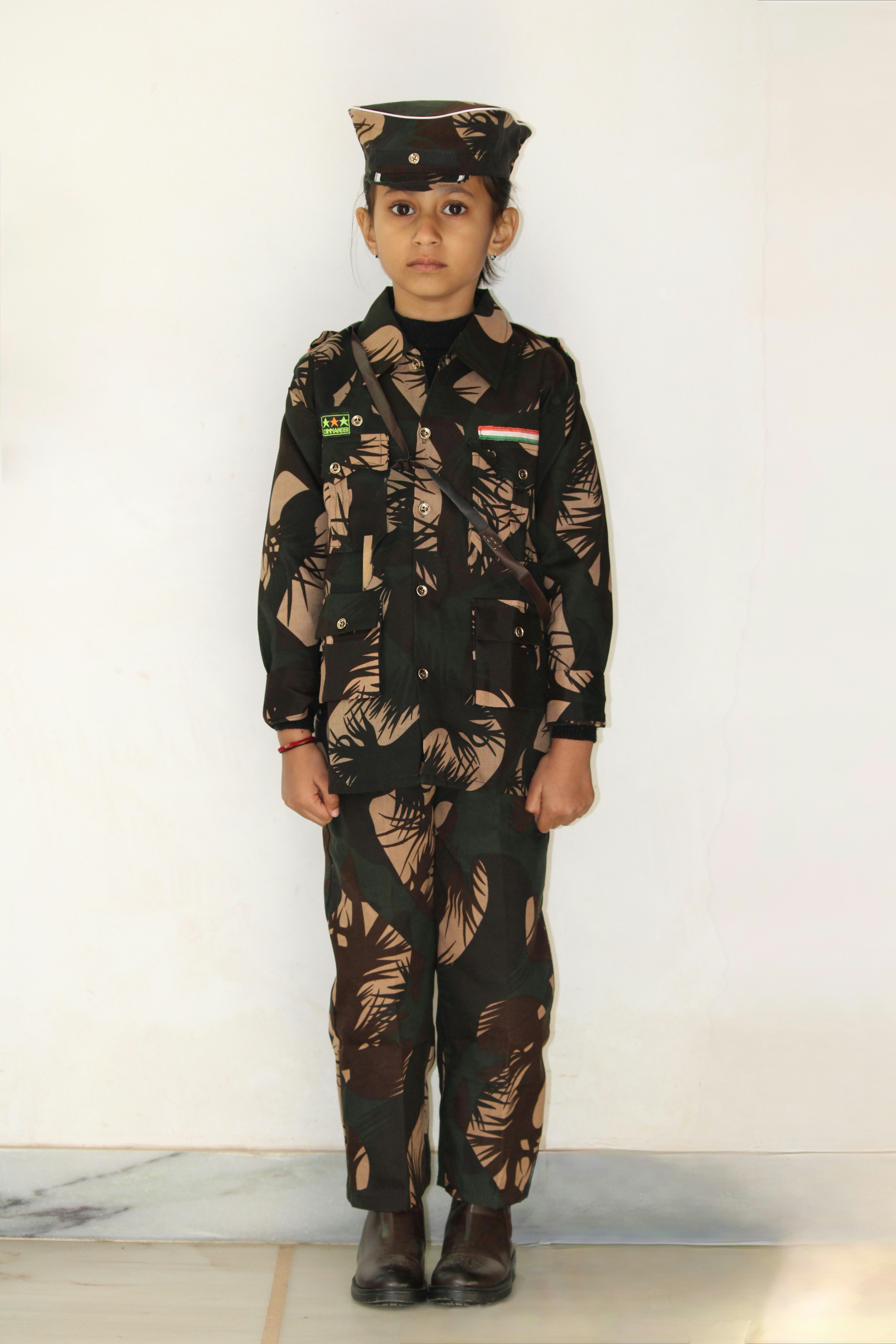Young child dressed in a indian military-inspired outfit, standing straight in natural light.