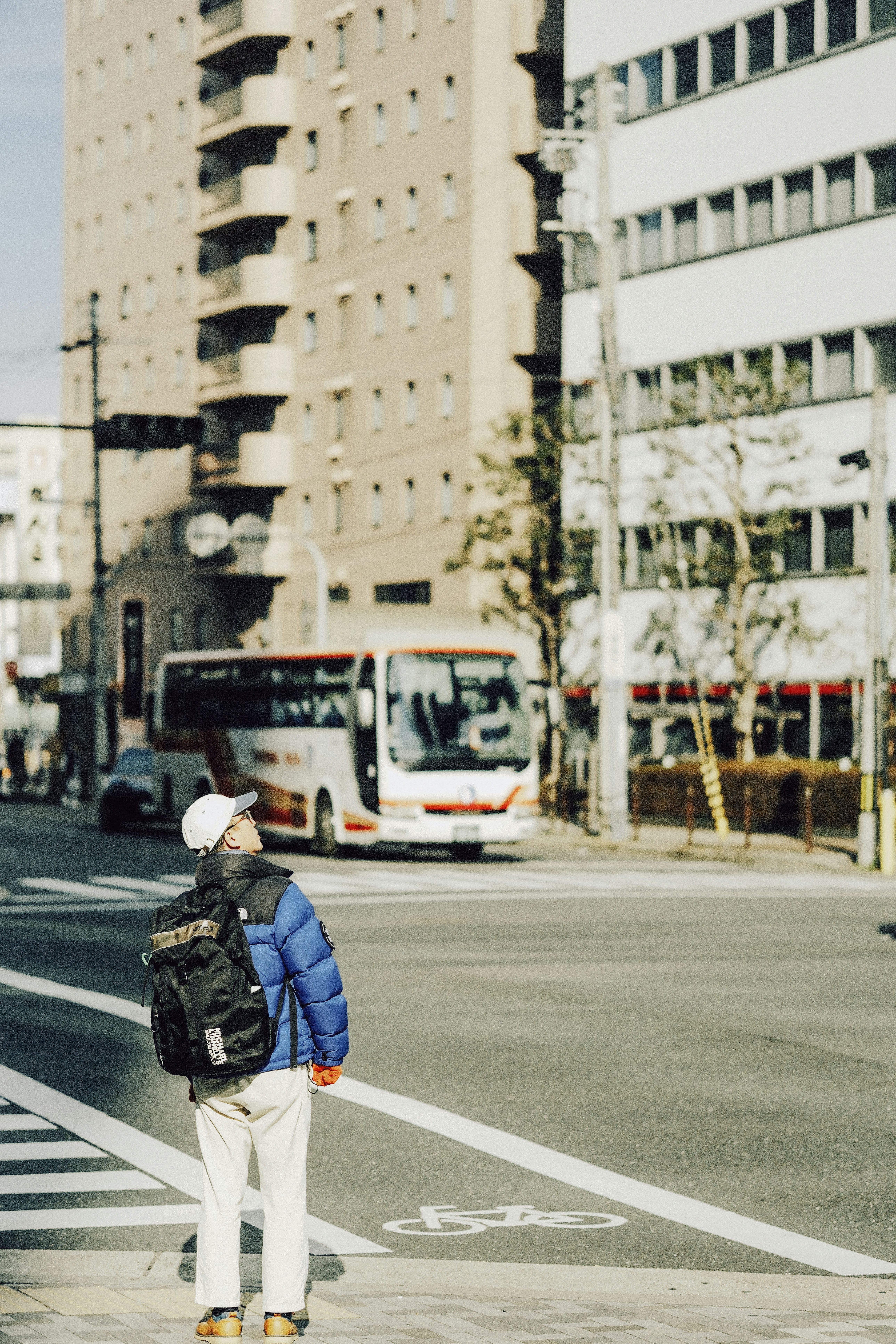Crosswalk Reverie: A Traveler Pauses Amid Urban Rhythm