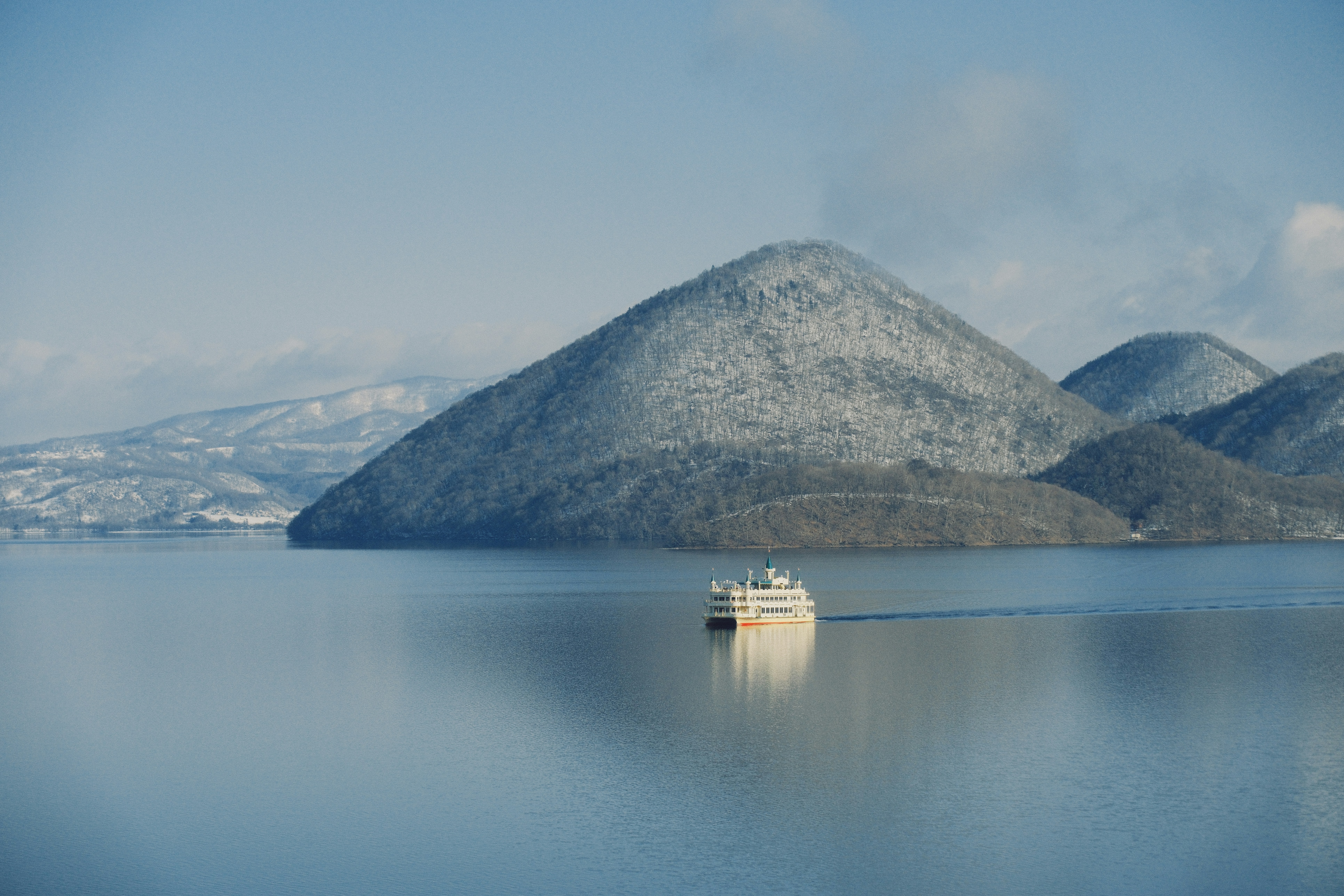 Solitary vessel gliding between chalky hills on a glassy sea