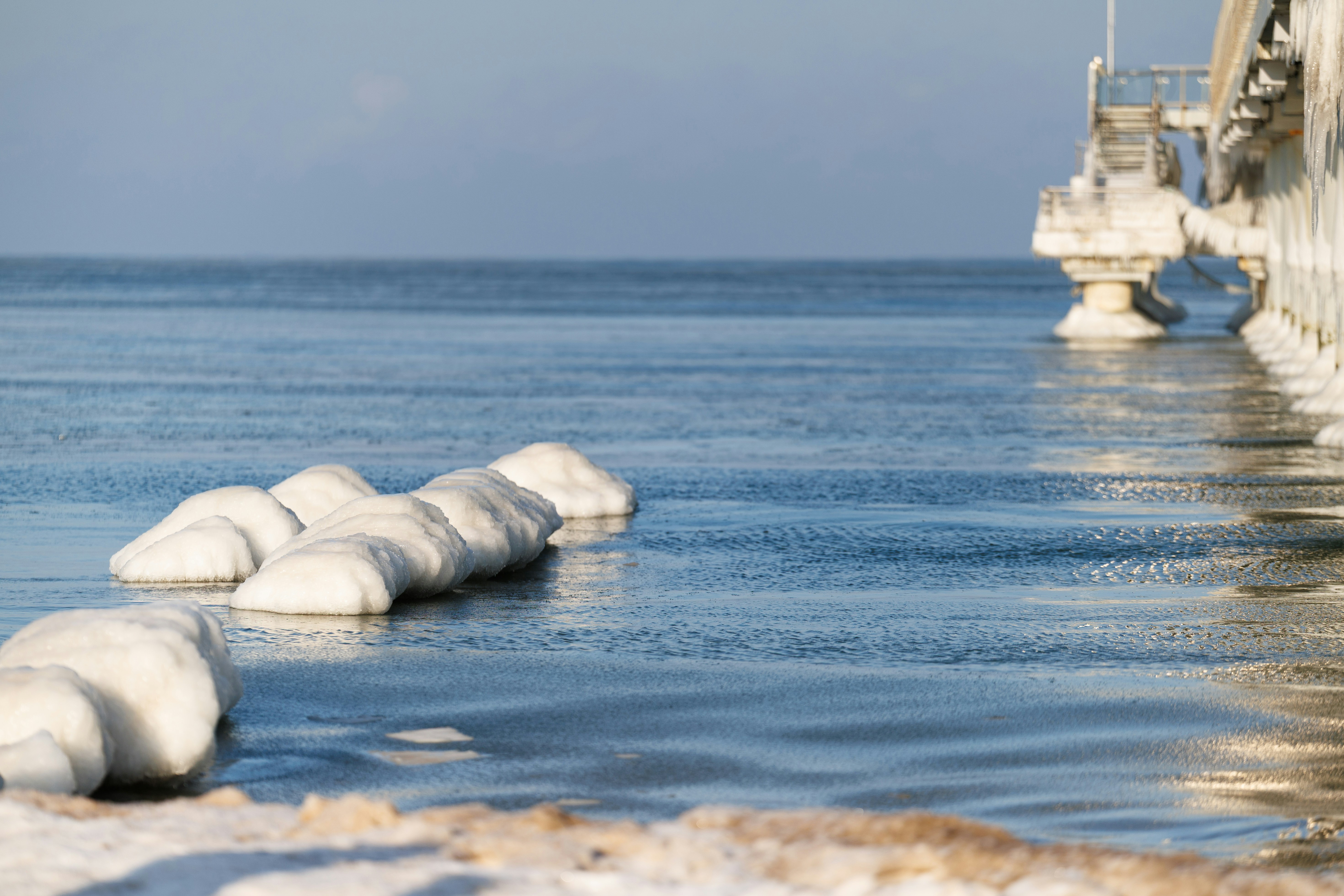Frozen Seascape: Snow-Piled Boulders and Distant Pier