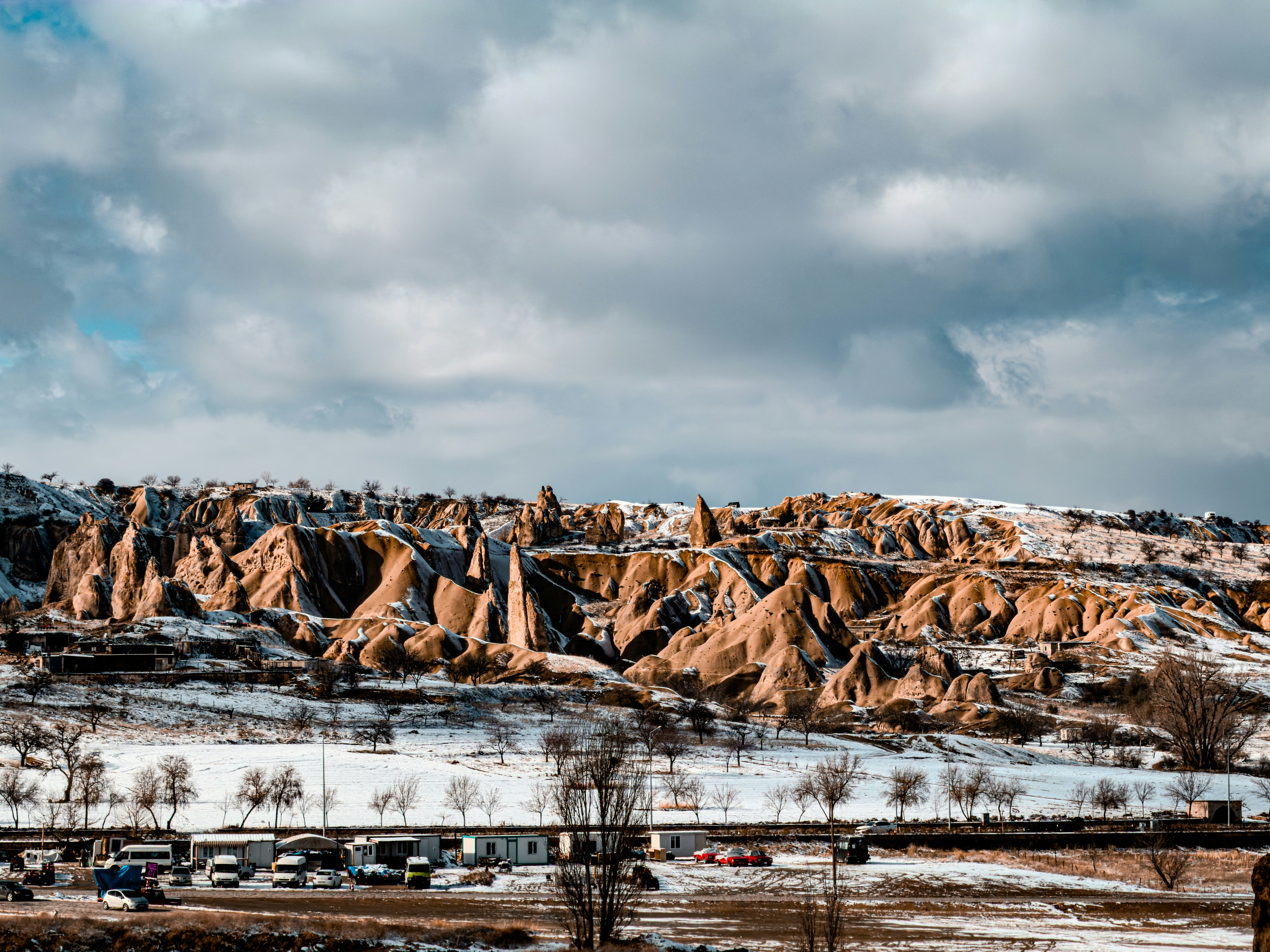 Snow-dusted badlands under a dramatic sky