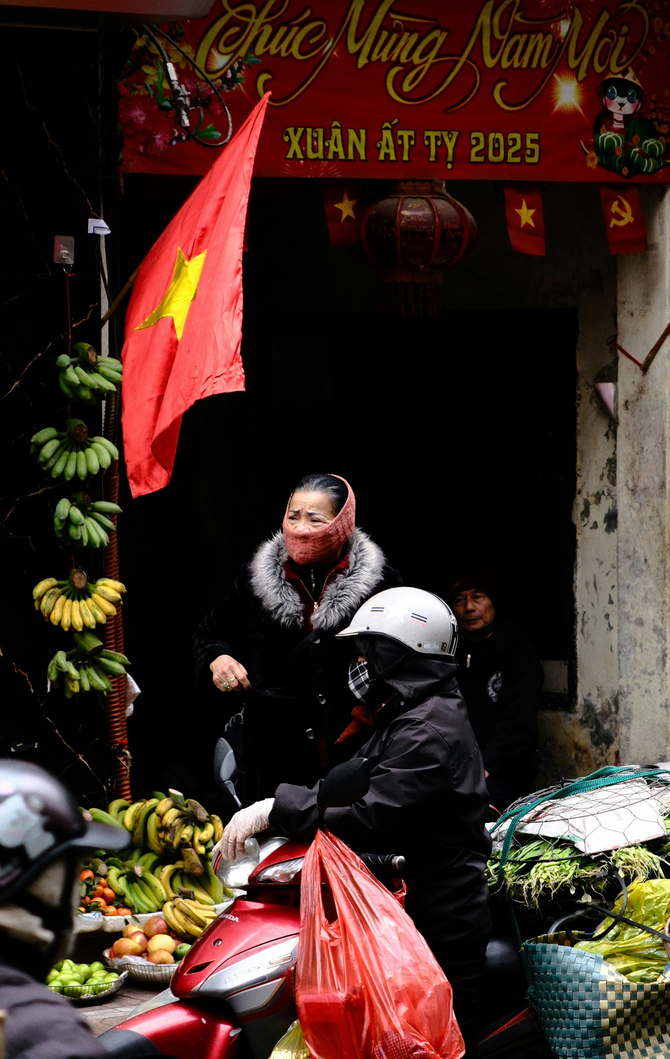 Face masked in a bustling Vietnamese street market under a festive banner