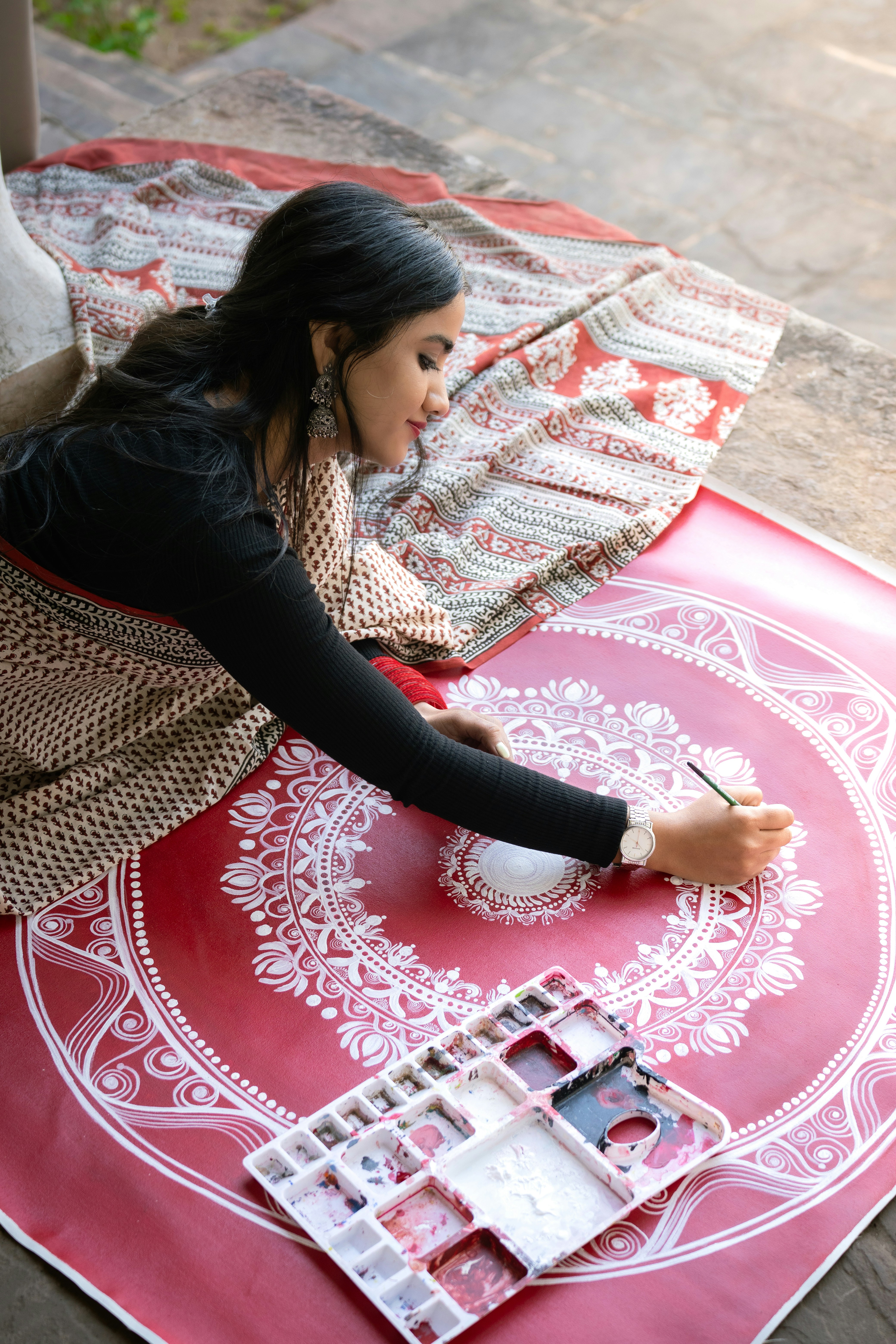 Hands at Work: The Artist Tracing a Circular Motif on Red Fabric