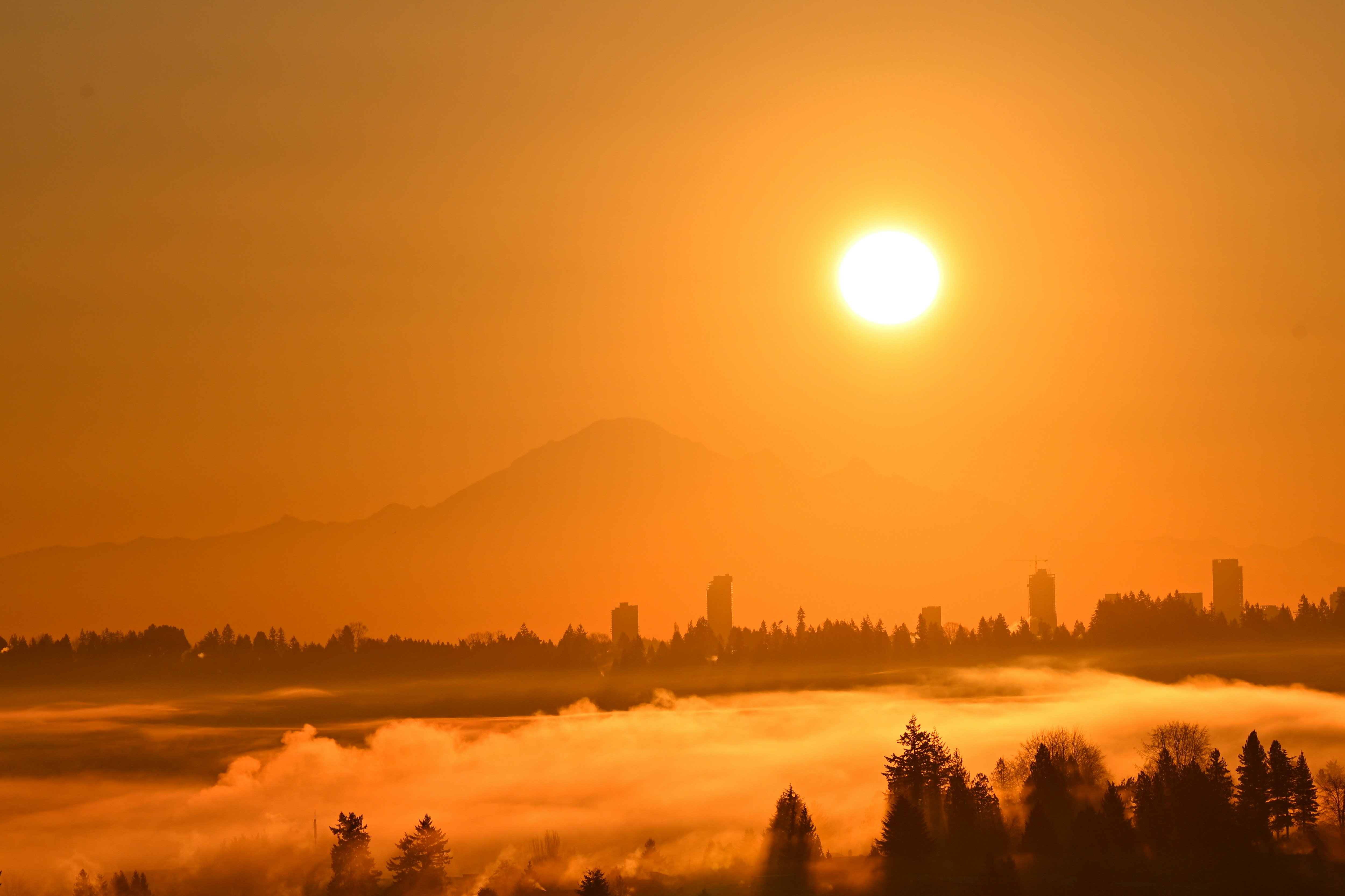 Sunlit Horizon: Volcano silhouette over a molten cityscape at dusk