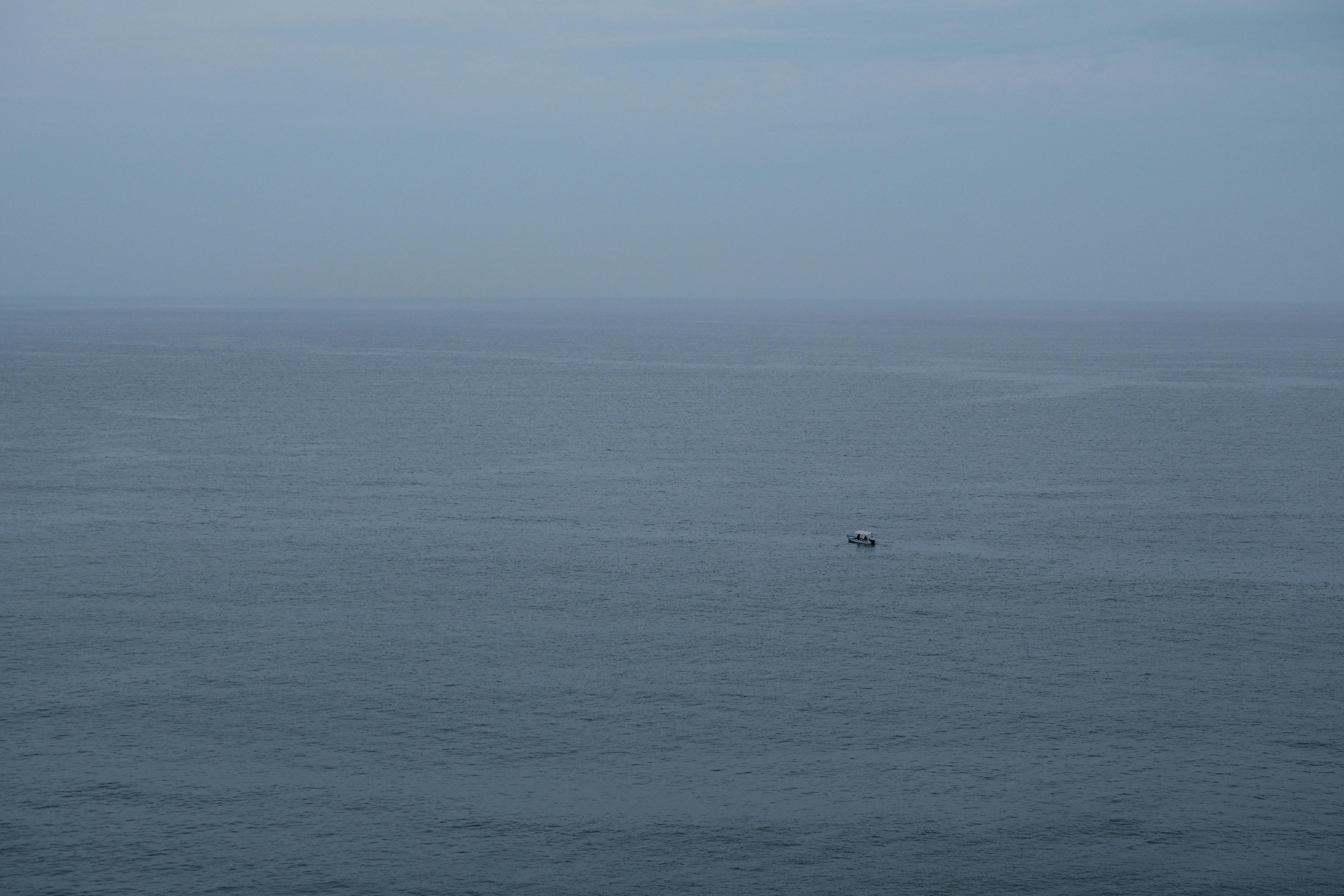 A lone vessel on a vast blue horizon