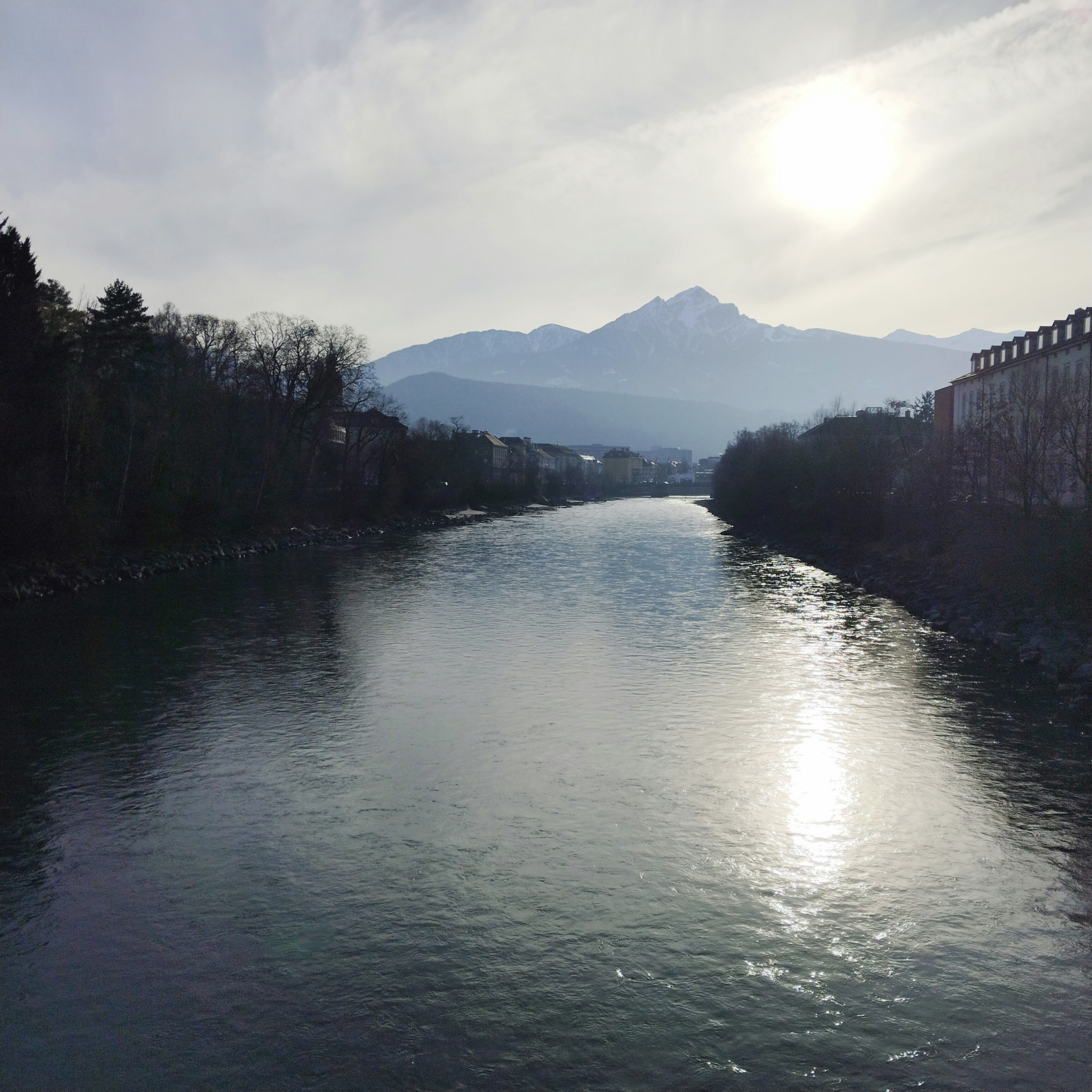 River flowing towards mountains under a hazy sun