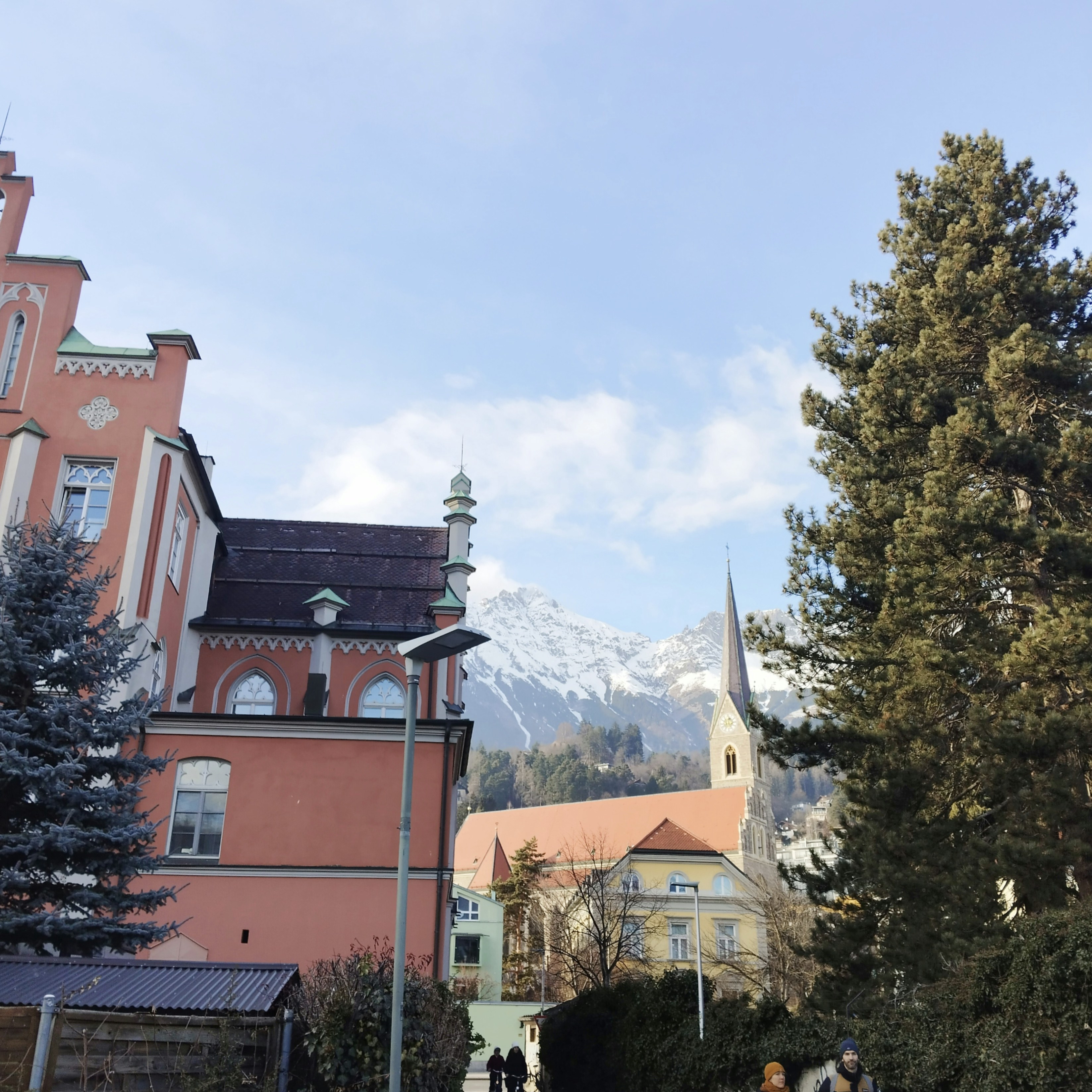 Pink building and church with snowy mountains behind.