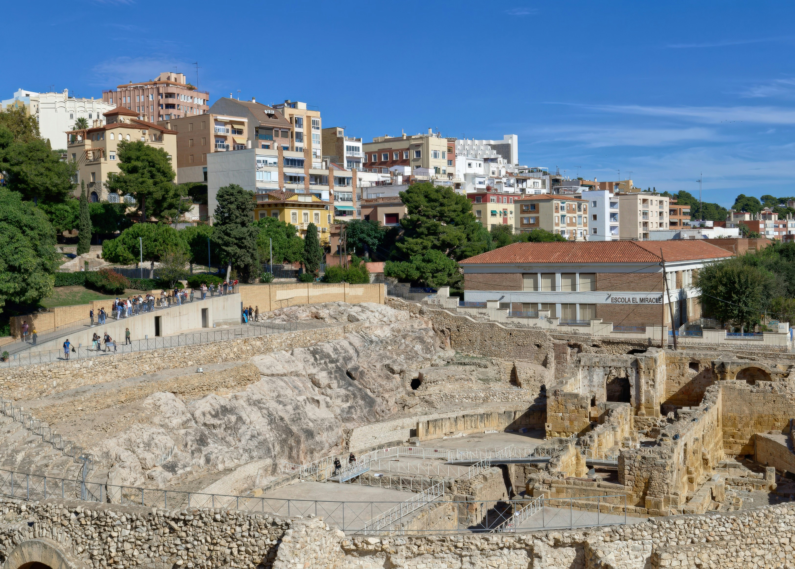 Ancient roman amphitheater with buildings in background.