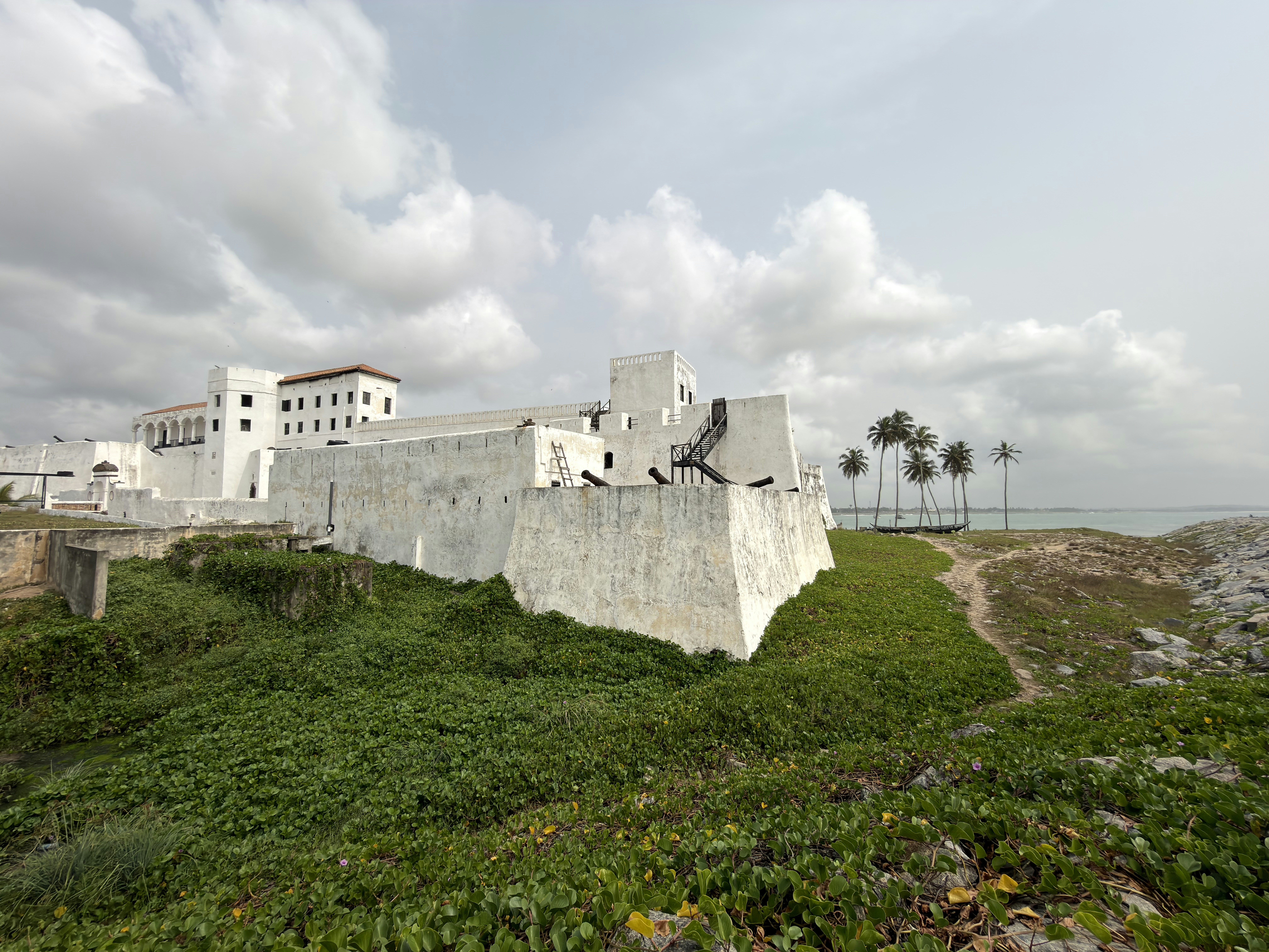 White fortress with cannons overlooking the ocean and palm trees