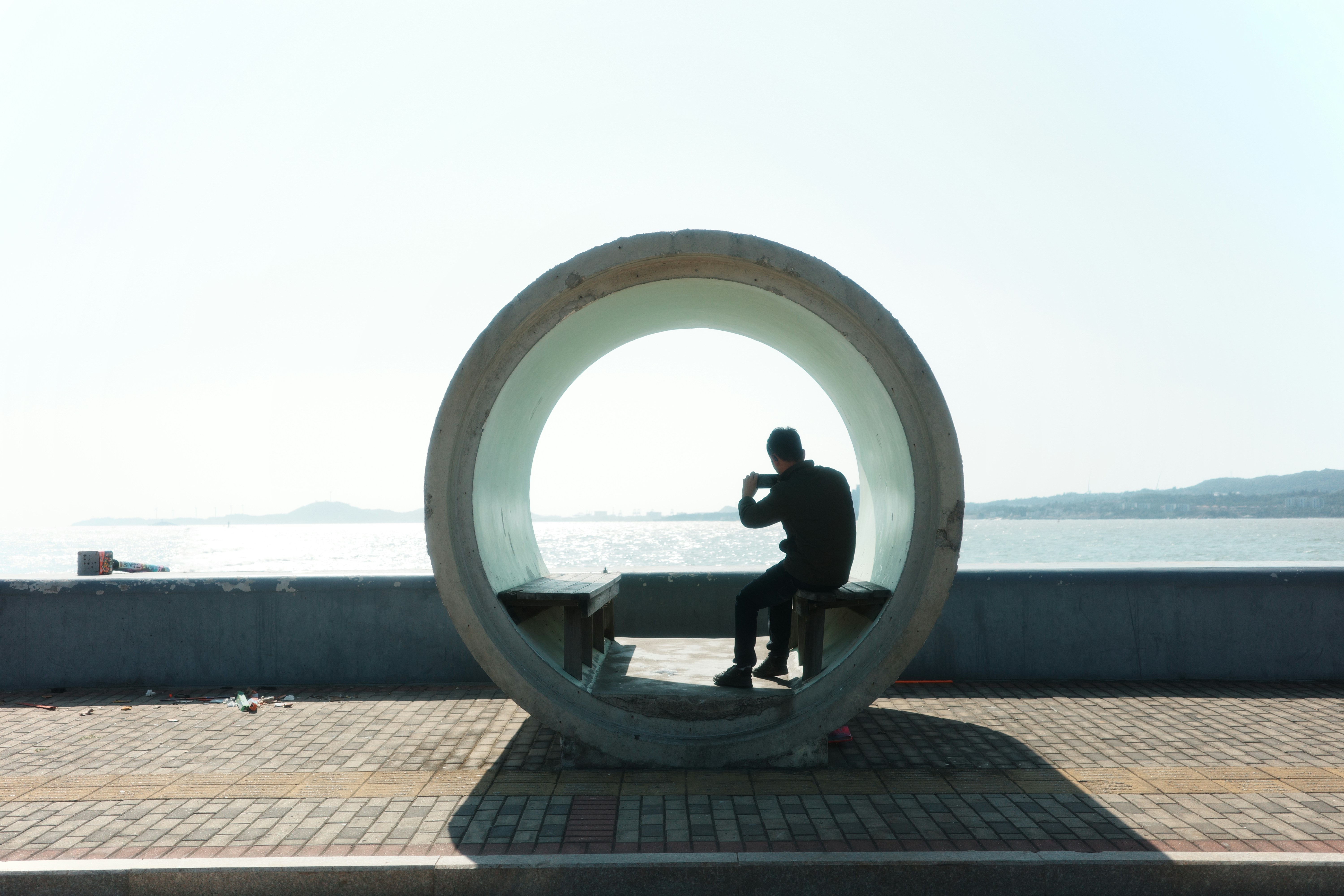 Circular Frame, Quiet Seascape: A photographer at the Pier