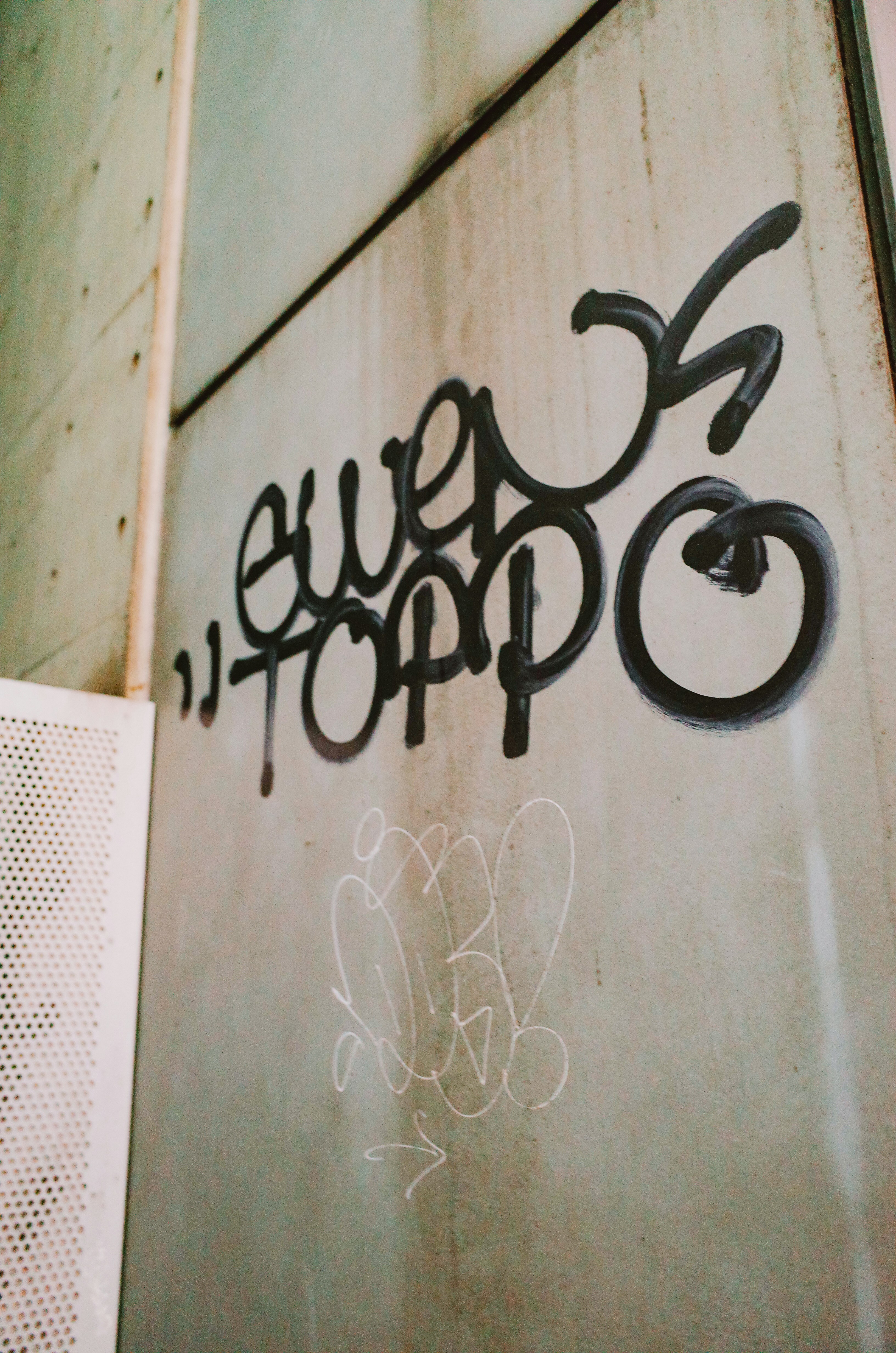 Curved Black Graffiti on Industrial Wall