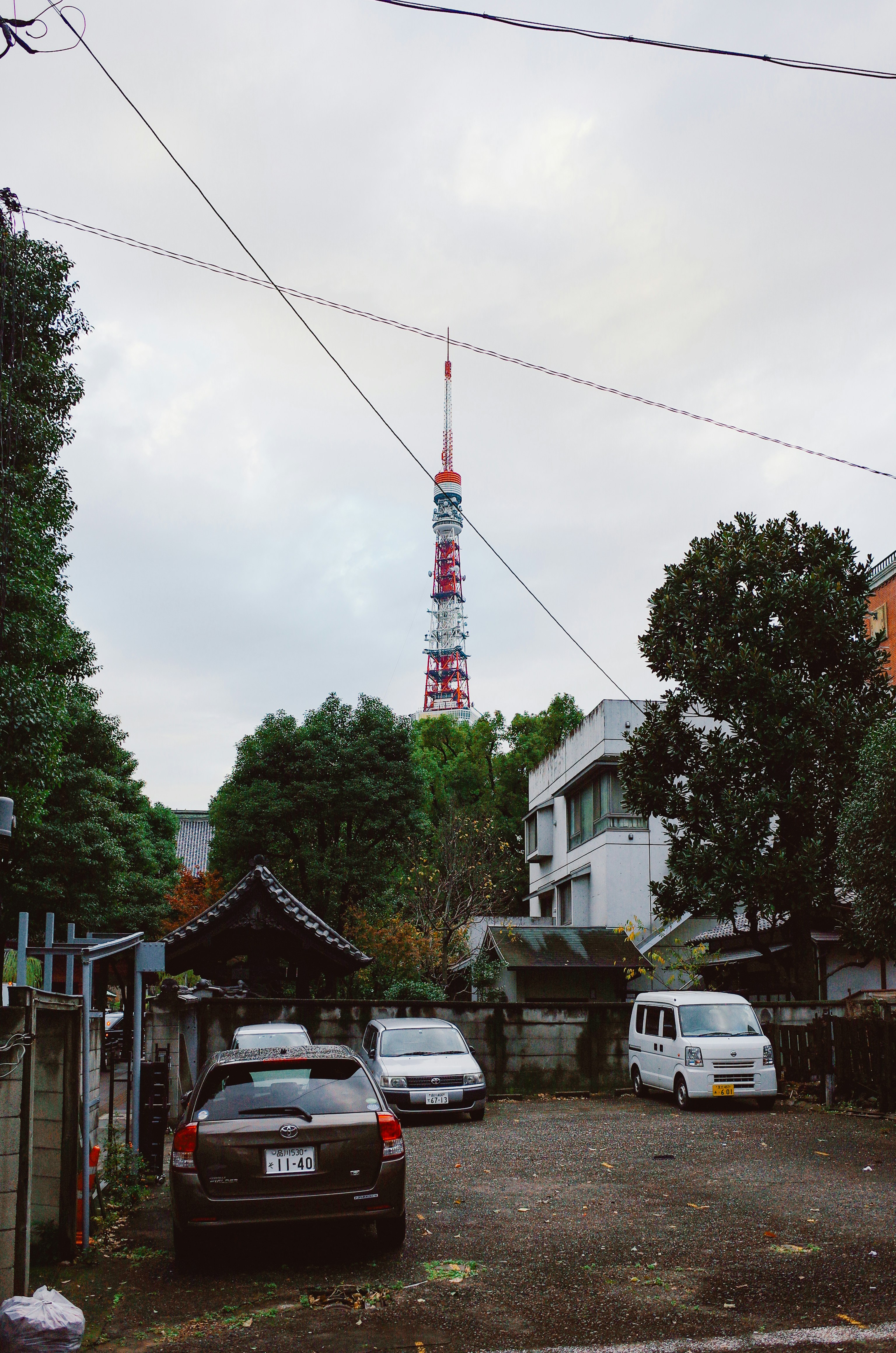 Urban Silence Under a Towering Signal: Cars, Roofs, and a Distant Antenna