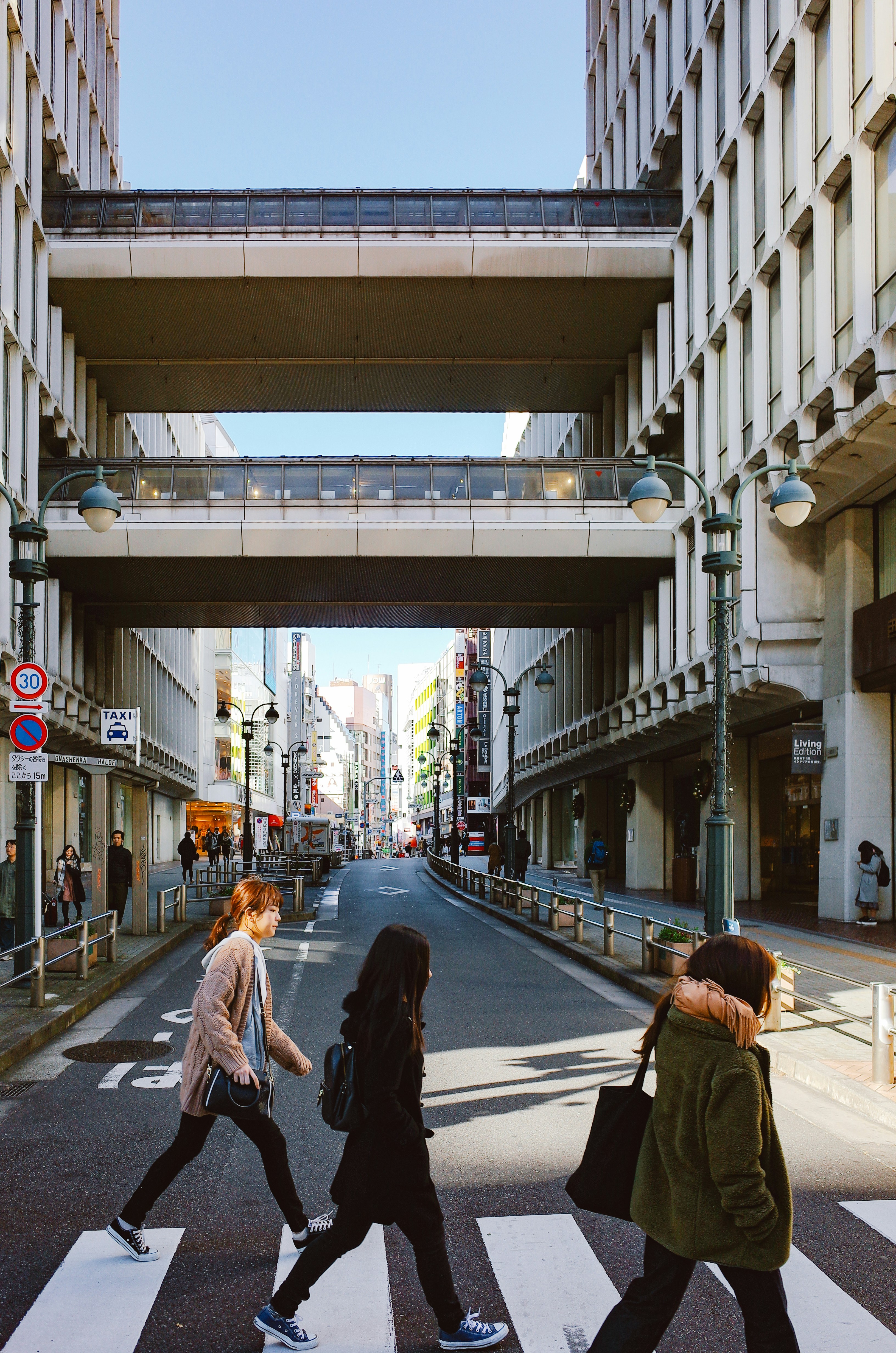 Three people cross a street in a city.