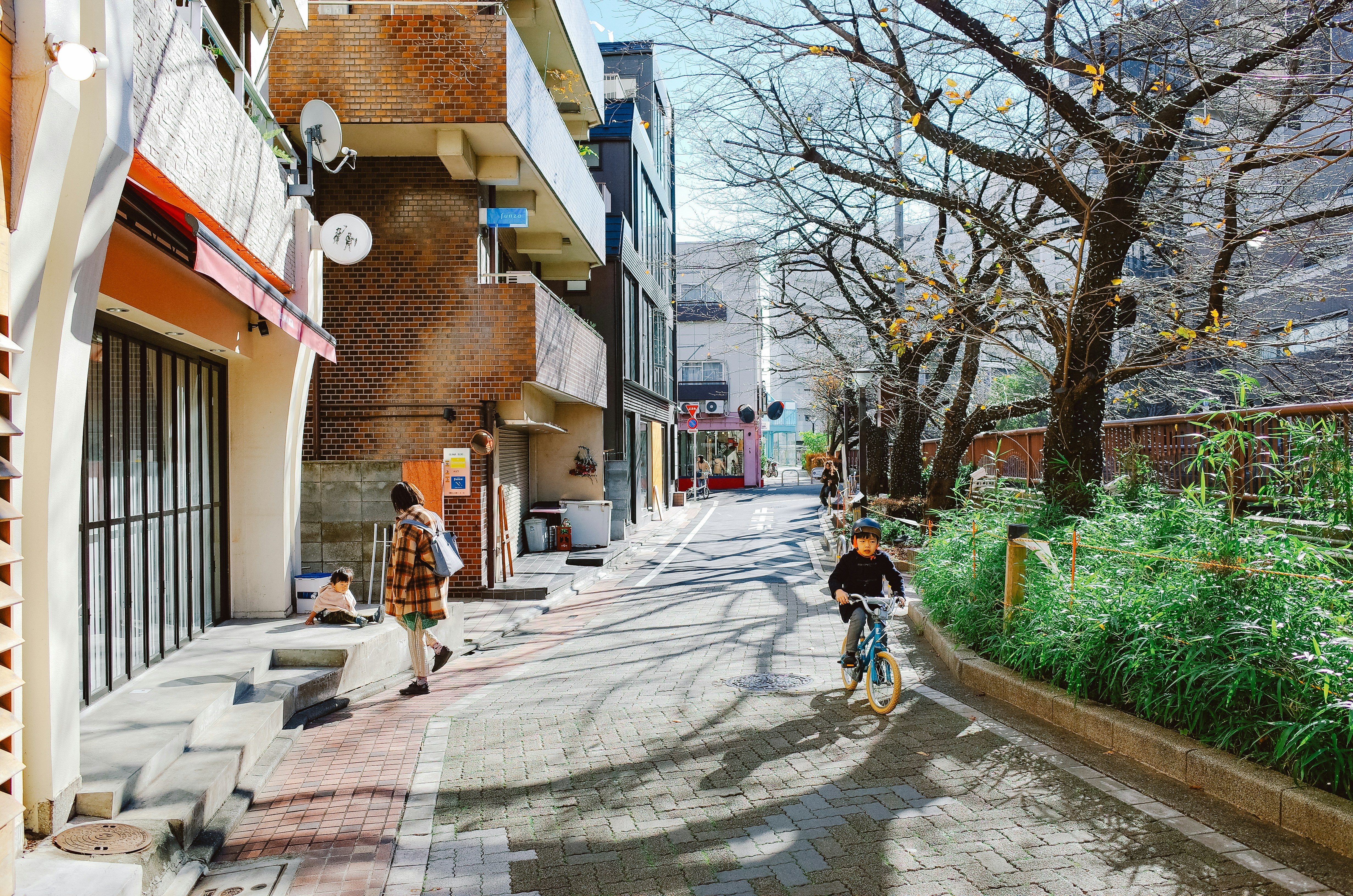 Sunlit Street Corridor: A Child on a Bike and a Peppered Playful Scene