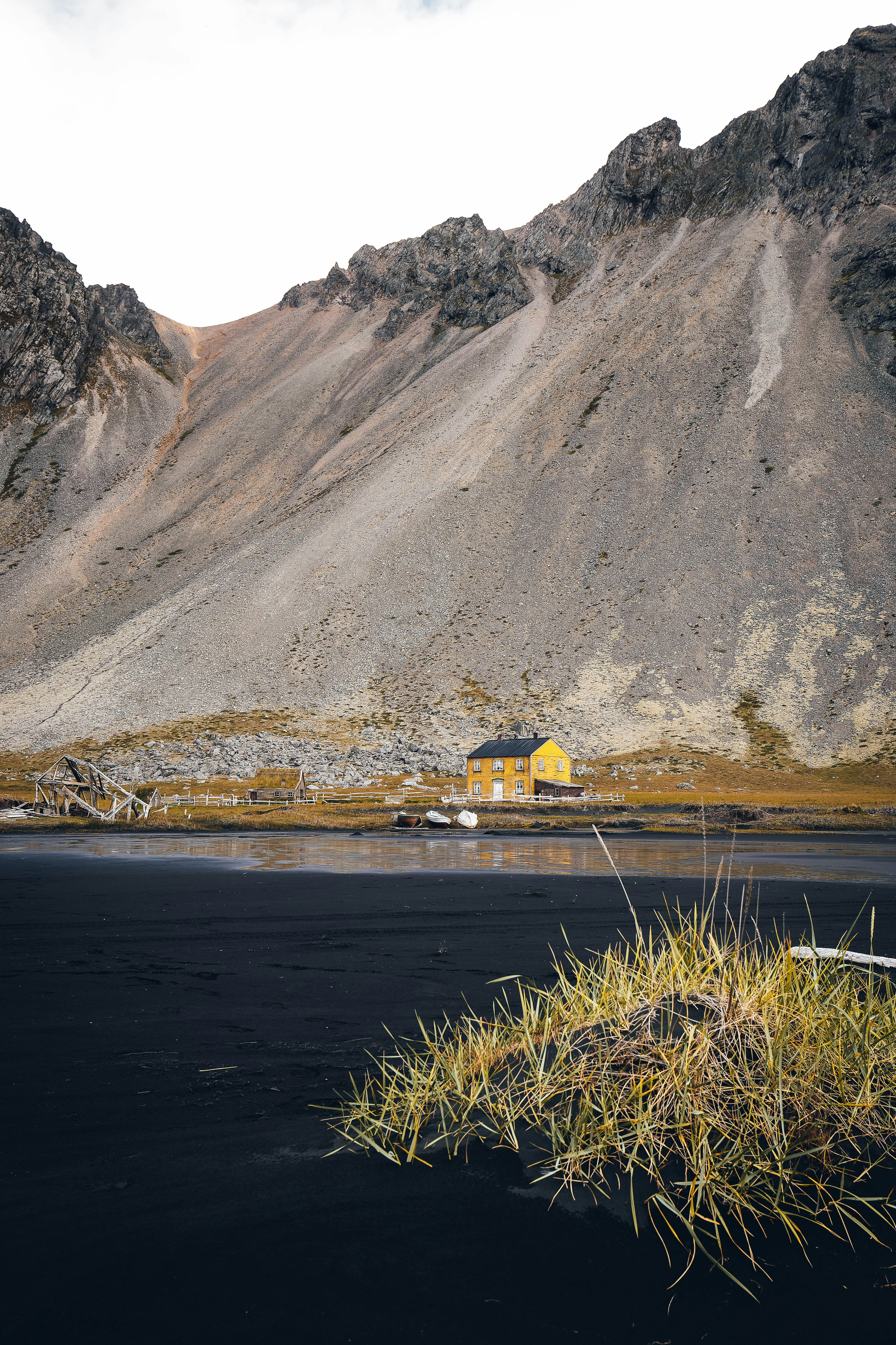 Small yellow house sits at the base of a mountain. photo – Free ...