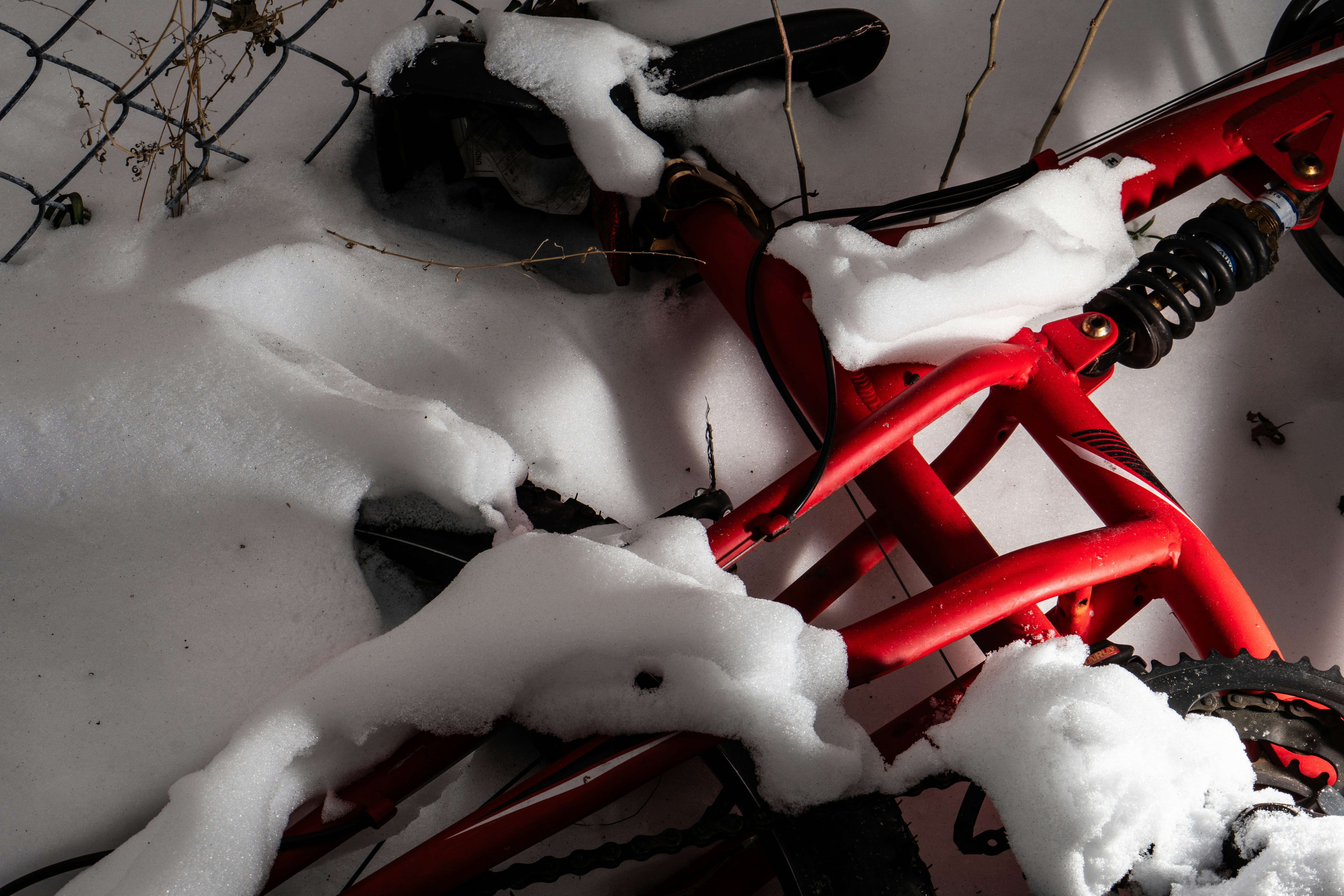 Crimson Frame Beneath Snow: A Snowbound Bike Resting in Winter Quiet