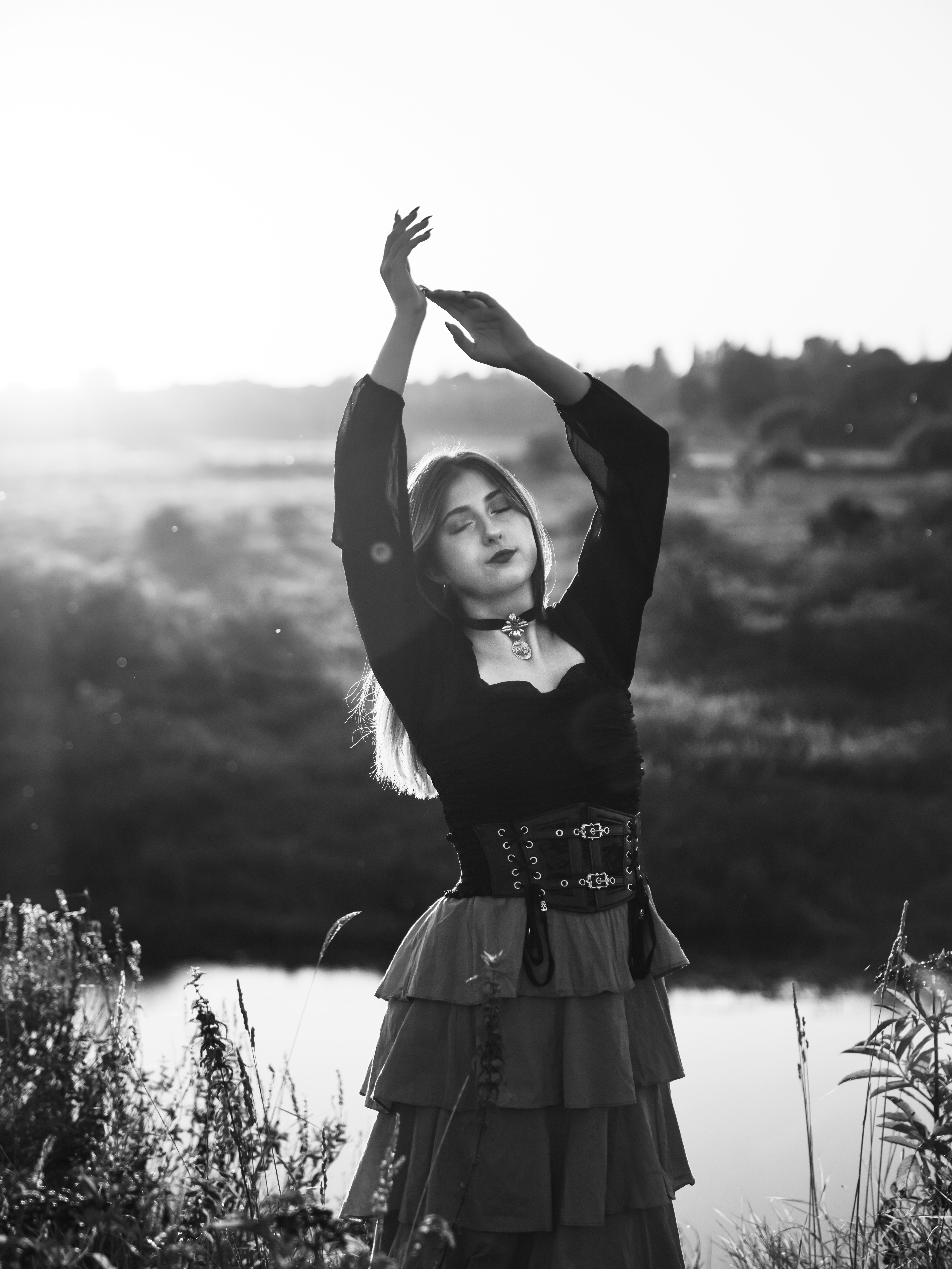 A woman in a corset and ruffled skirt poses outdoors.