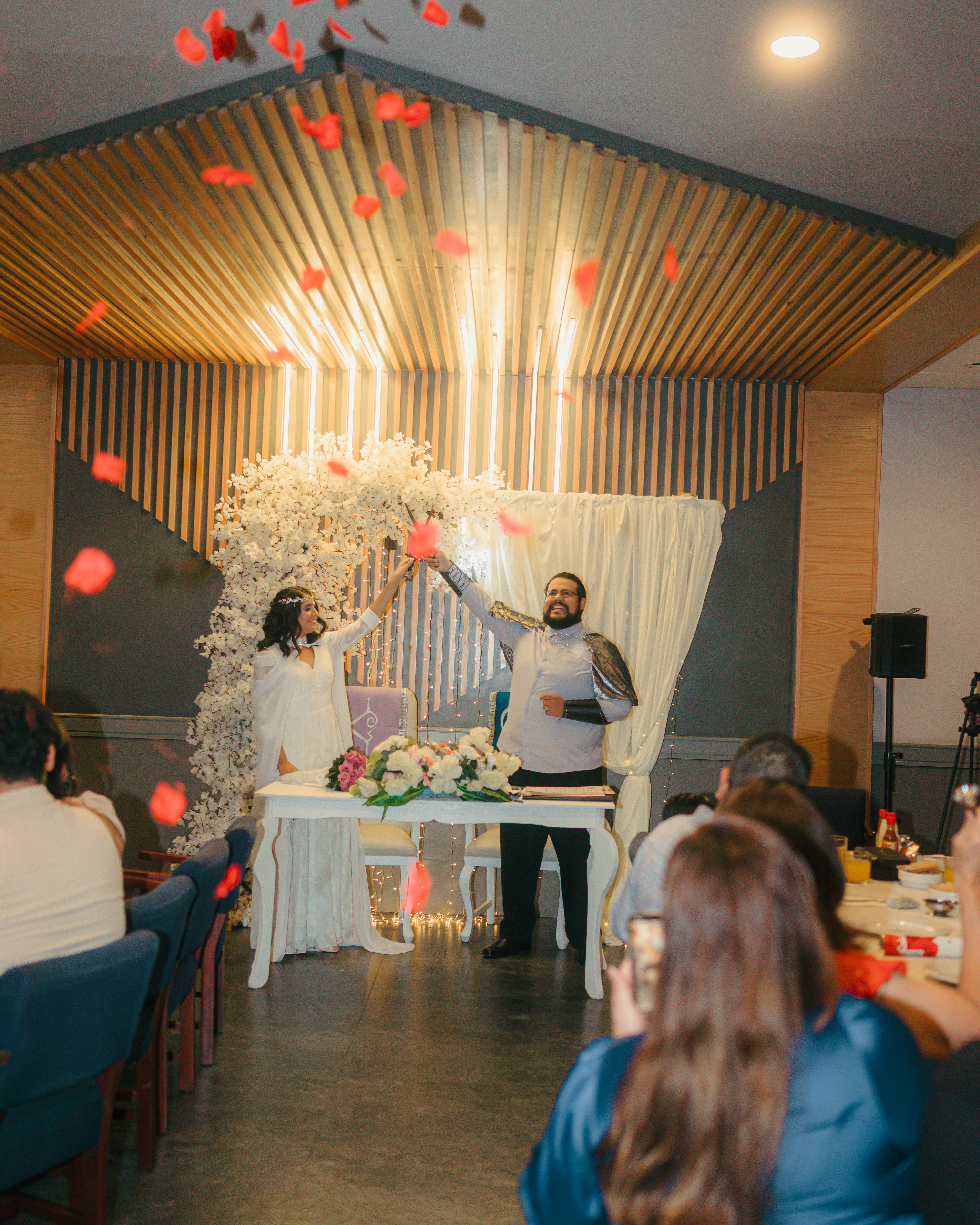 Toast at the Arch: A Joyful Exchange Beneath Confetti and Wedding Florals