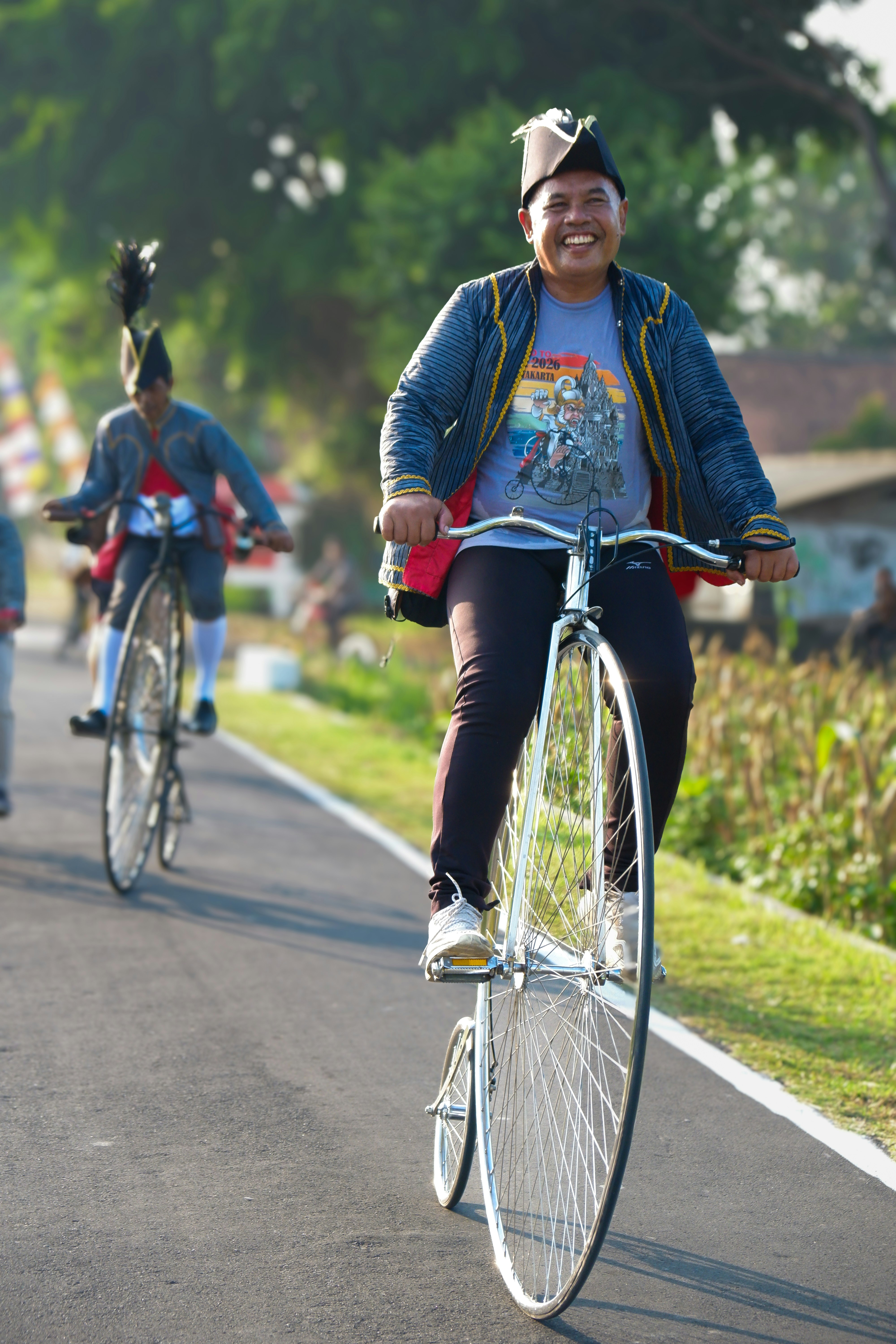 Cyclist in a bright blue jacket leads a cheerful parade on a sunny road