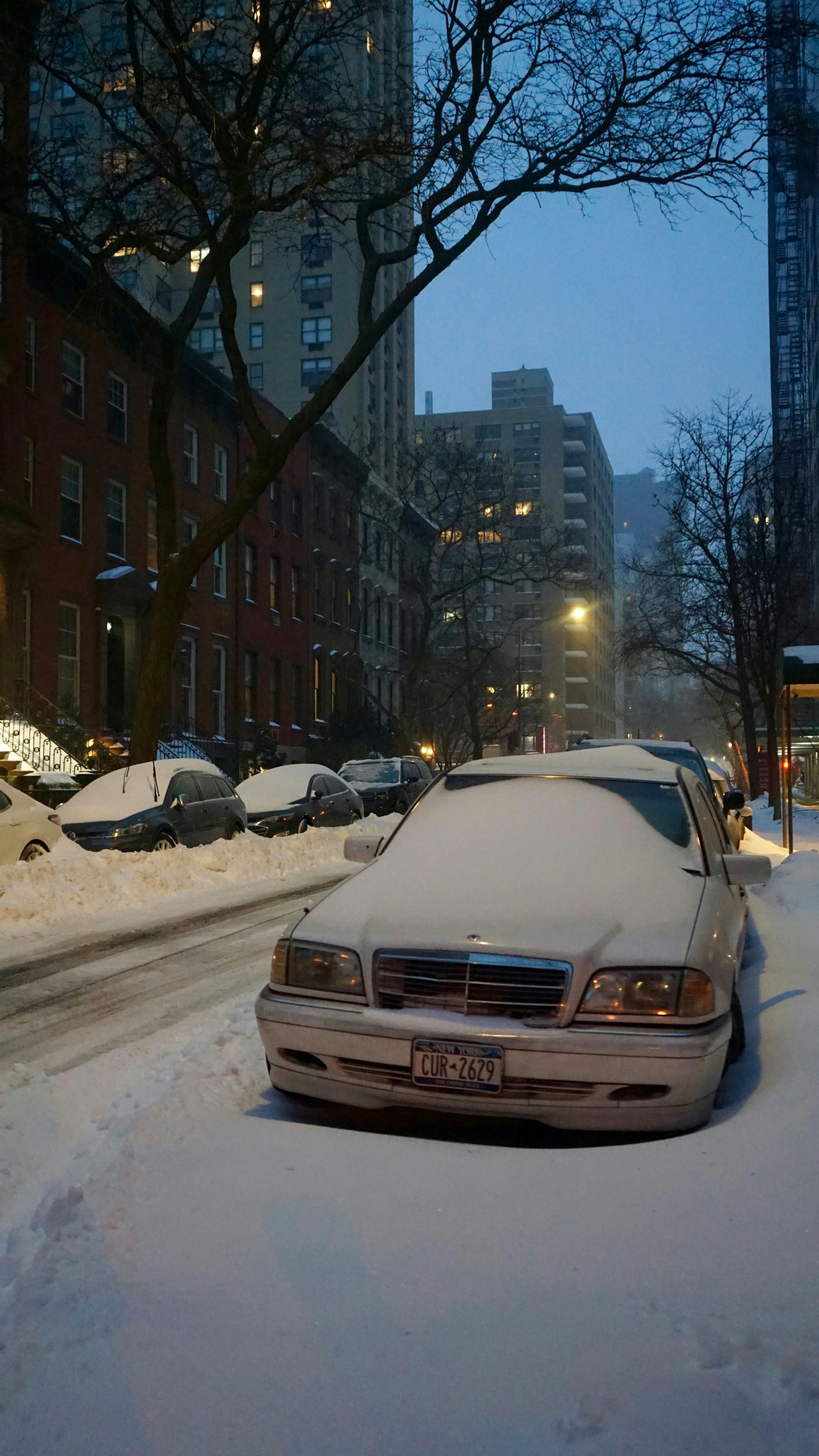 Snowbound Sedan on a Quiet Urban Street at Dusk