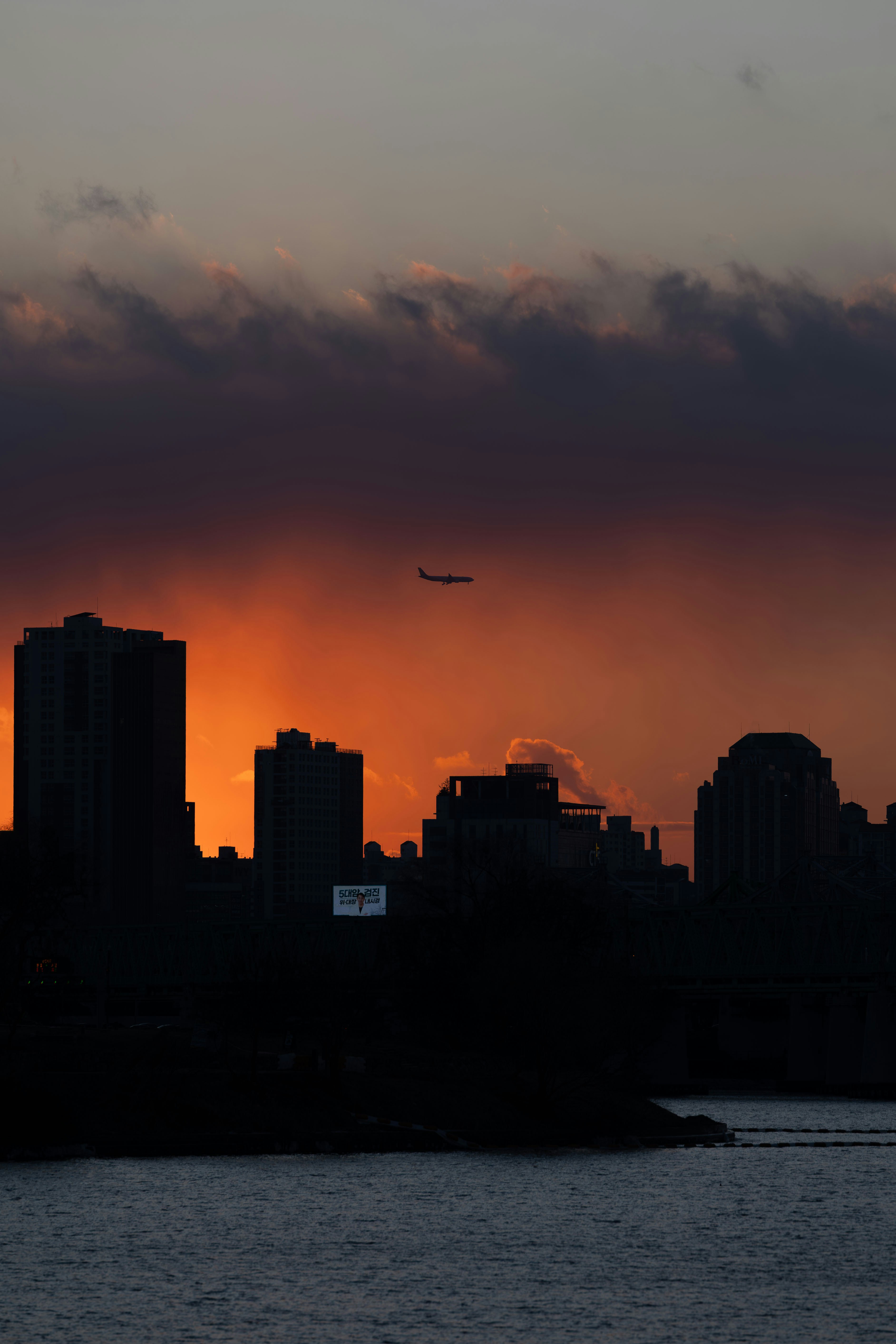 Silhouette Skyline at Sunset: A Plane Crossing the Fiery Horizon