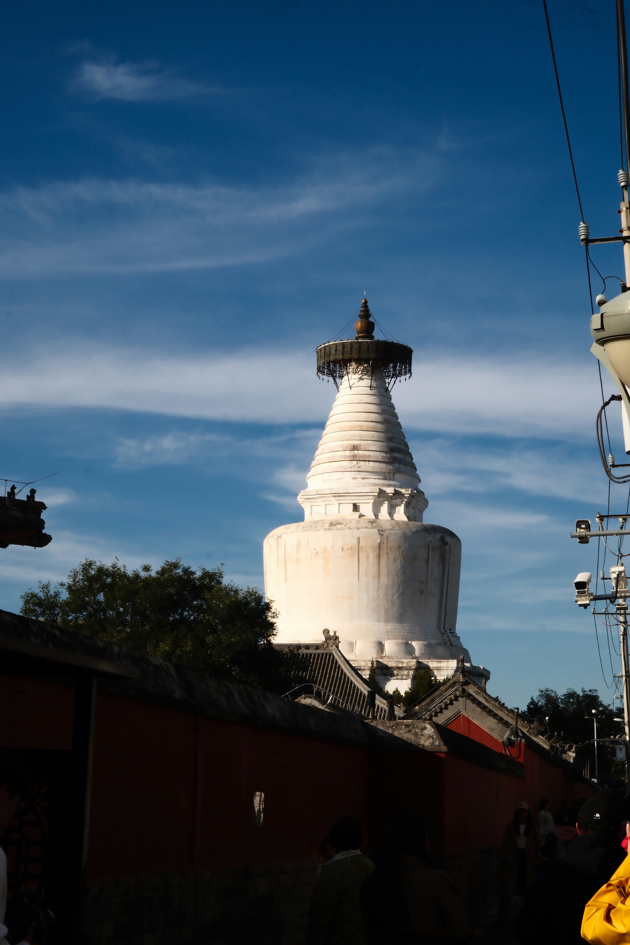 White Stupa Rising Over the Red Wall in a Quiet Street