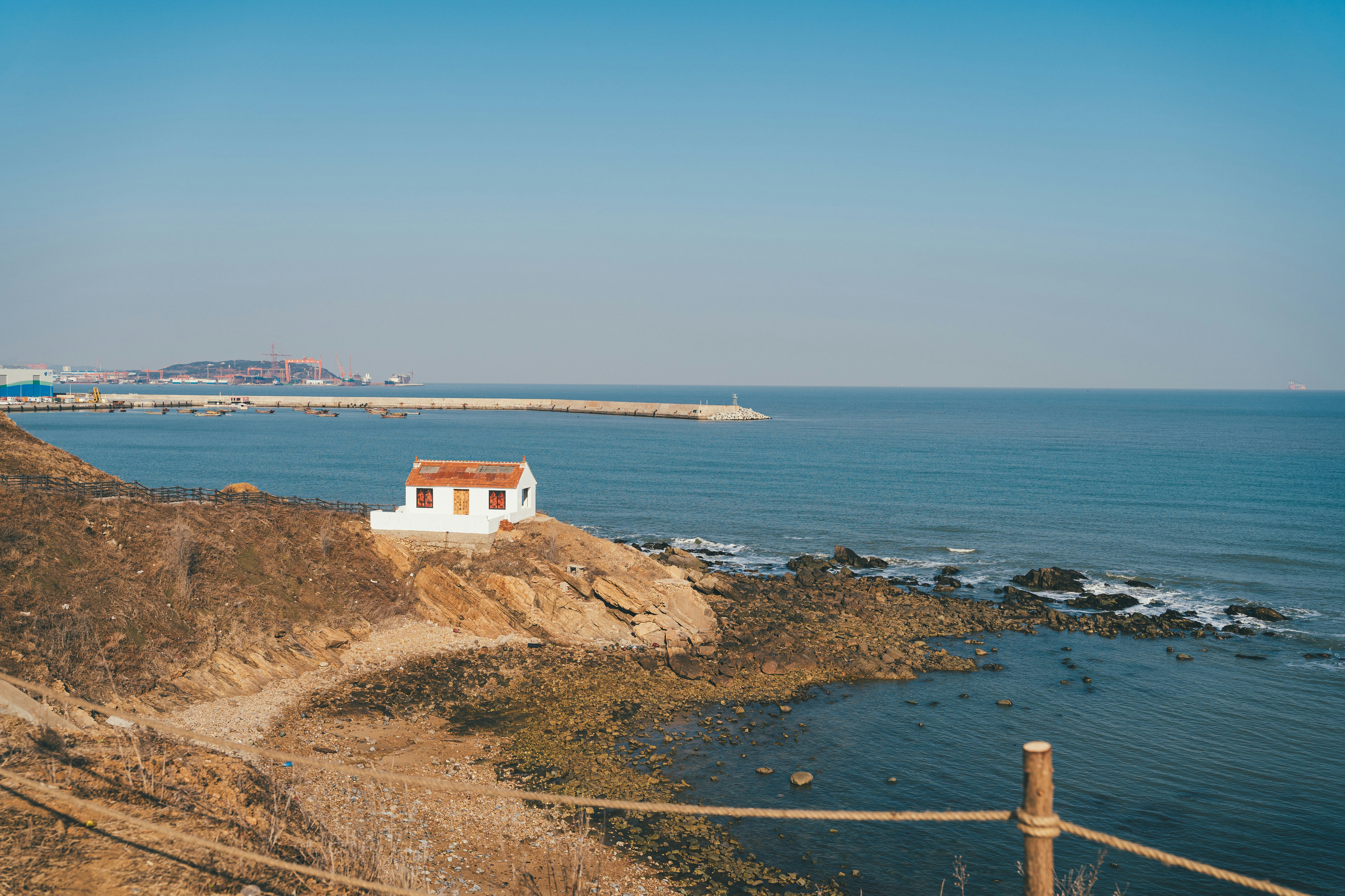 Coastal Outpost: A Small White Building Anchored on Rocky Terrain
