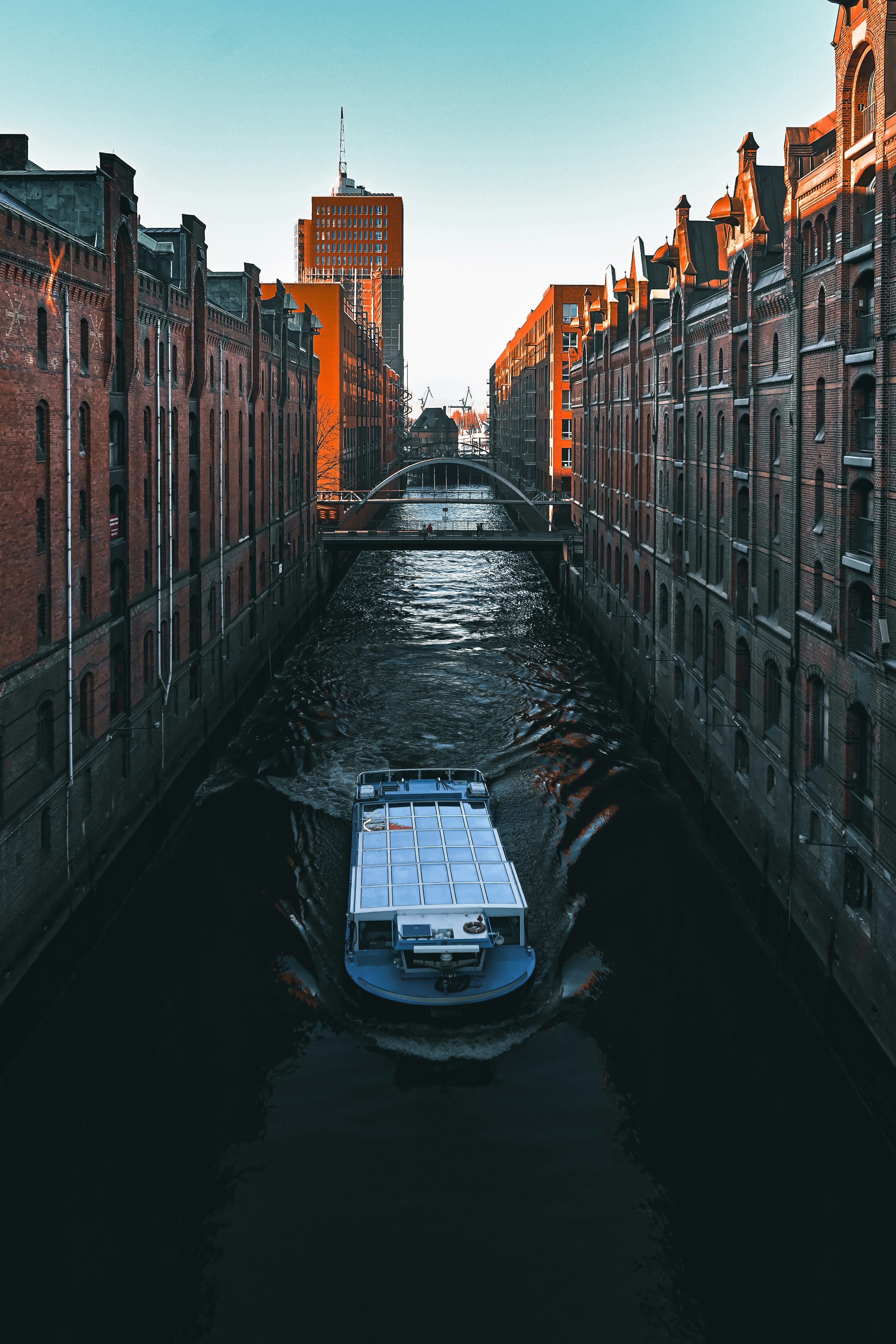 Towpath Transit: A Boat Drifts Between Brick Giants