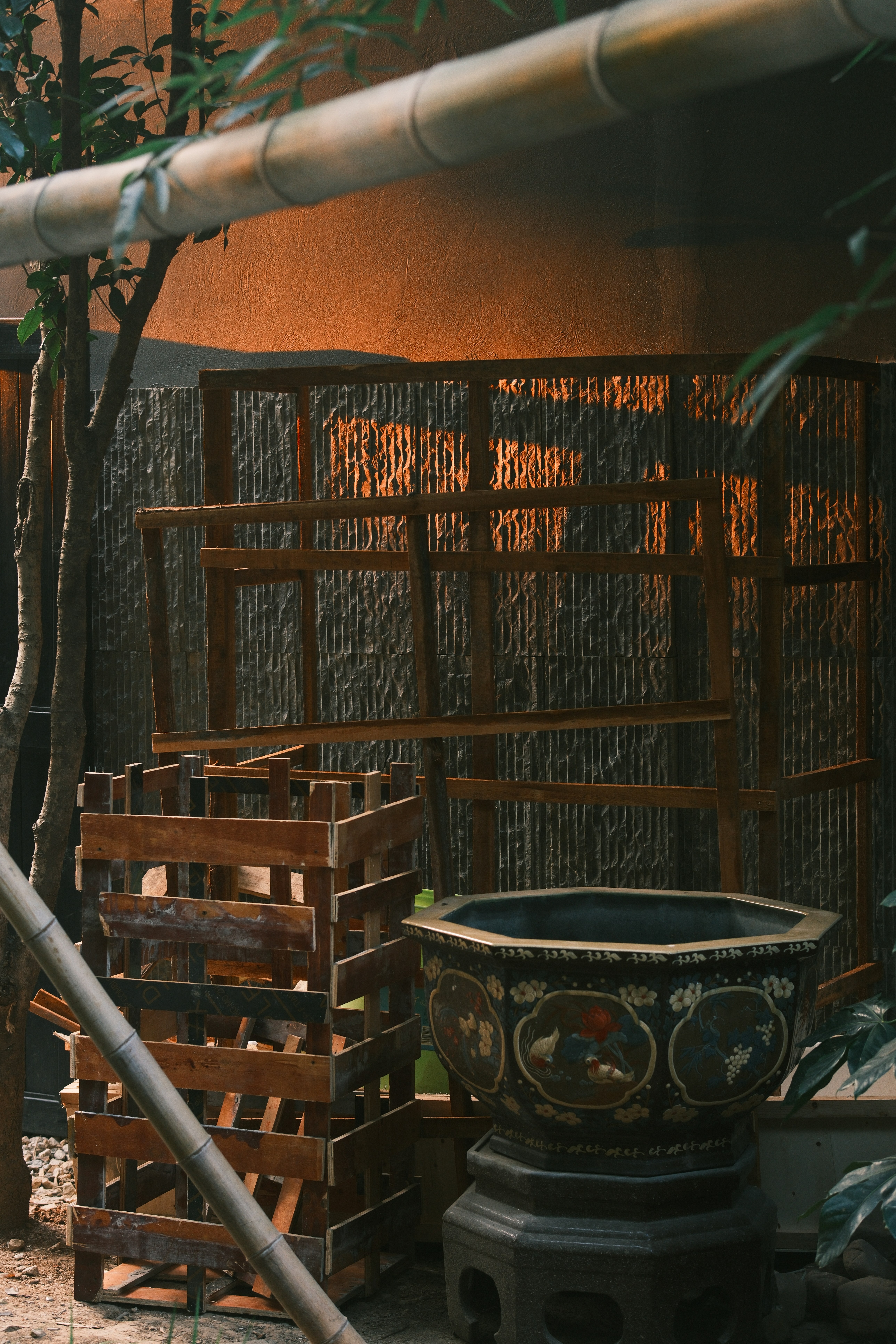 Terracotta garden vignette: stacked crates and a ceremonial pot in warm light
