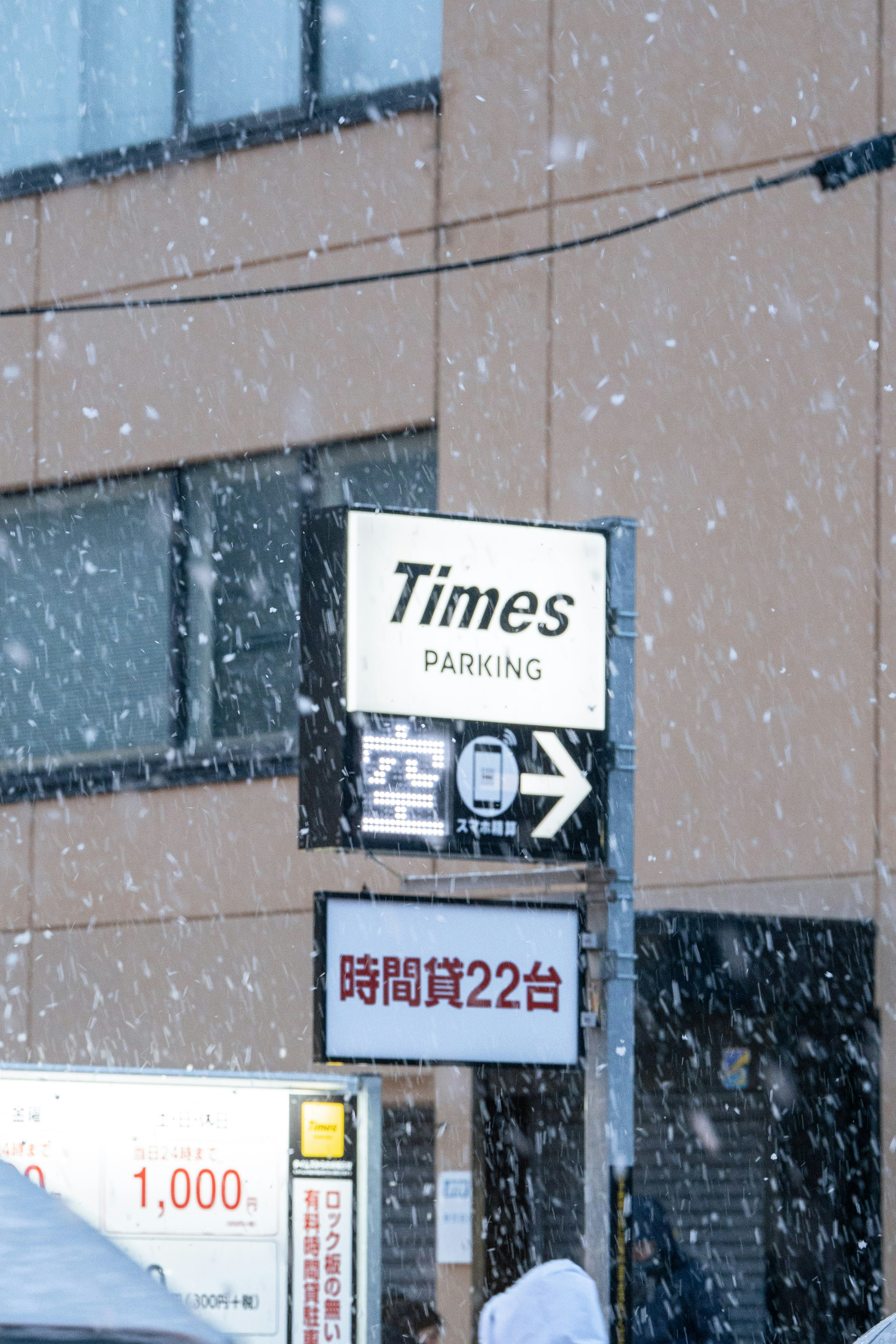 Times Parking Sign in Snowfall near a Modern Building