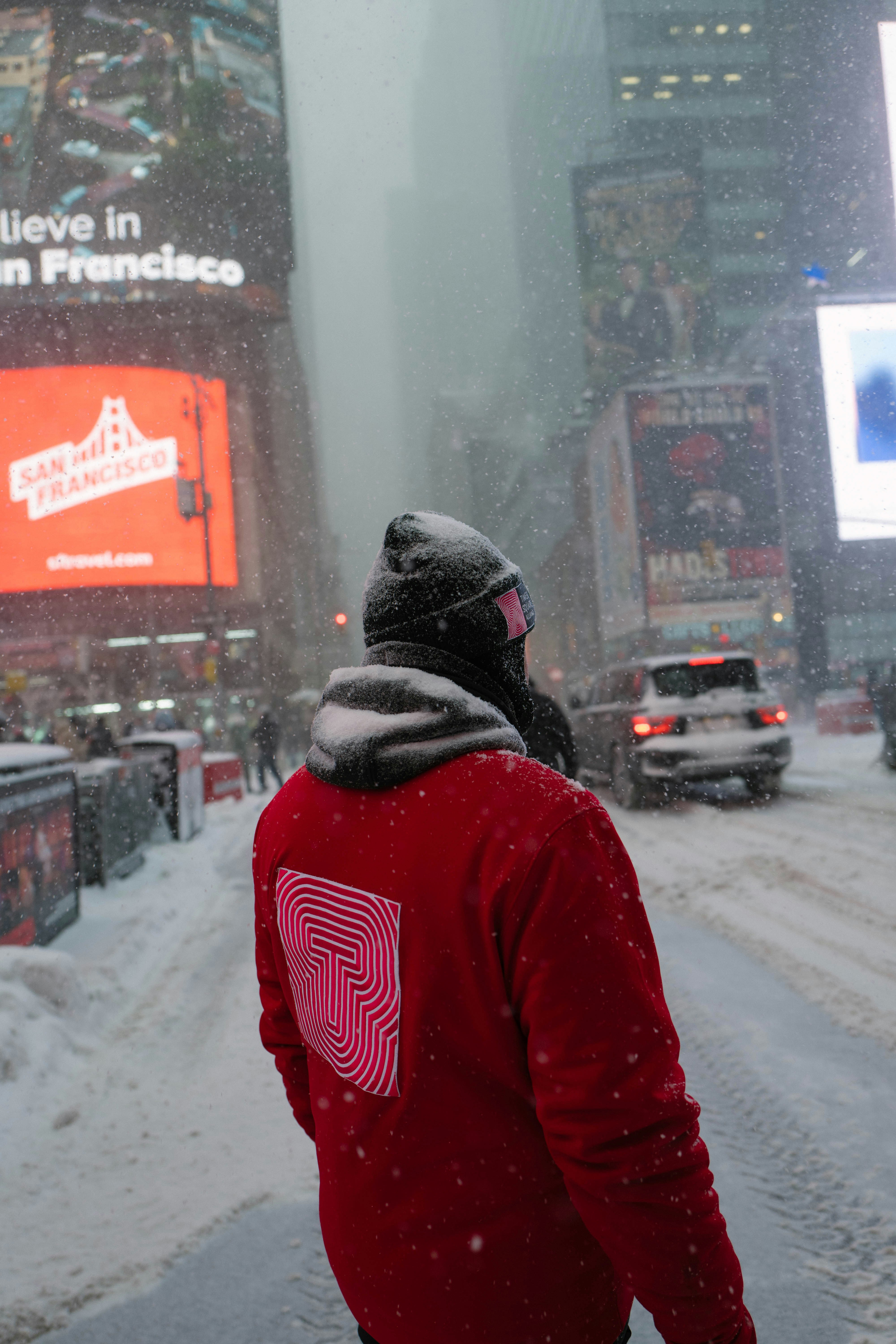 Red Hoodie in Snowfall: City Lights Blur the Frame