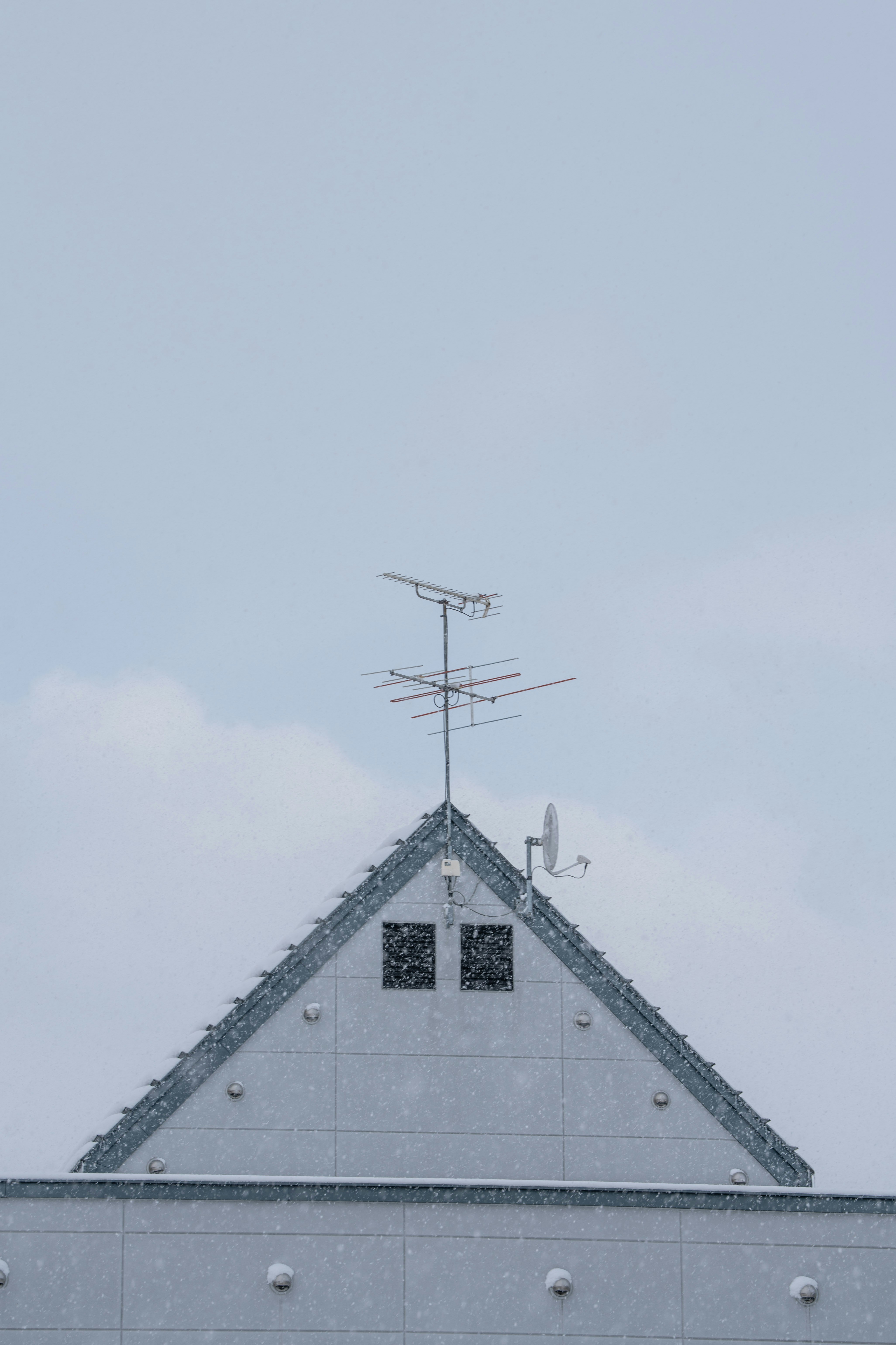Symmetrical Rooftop Pose: Antenna Stack Beneath a Clear Sky