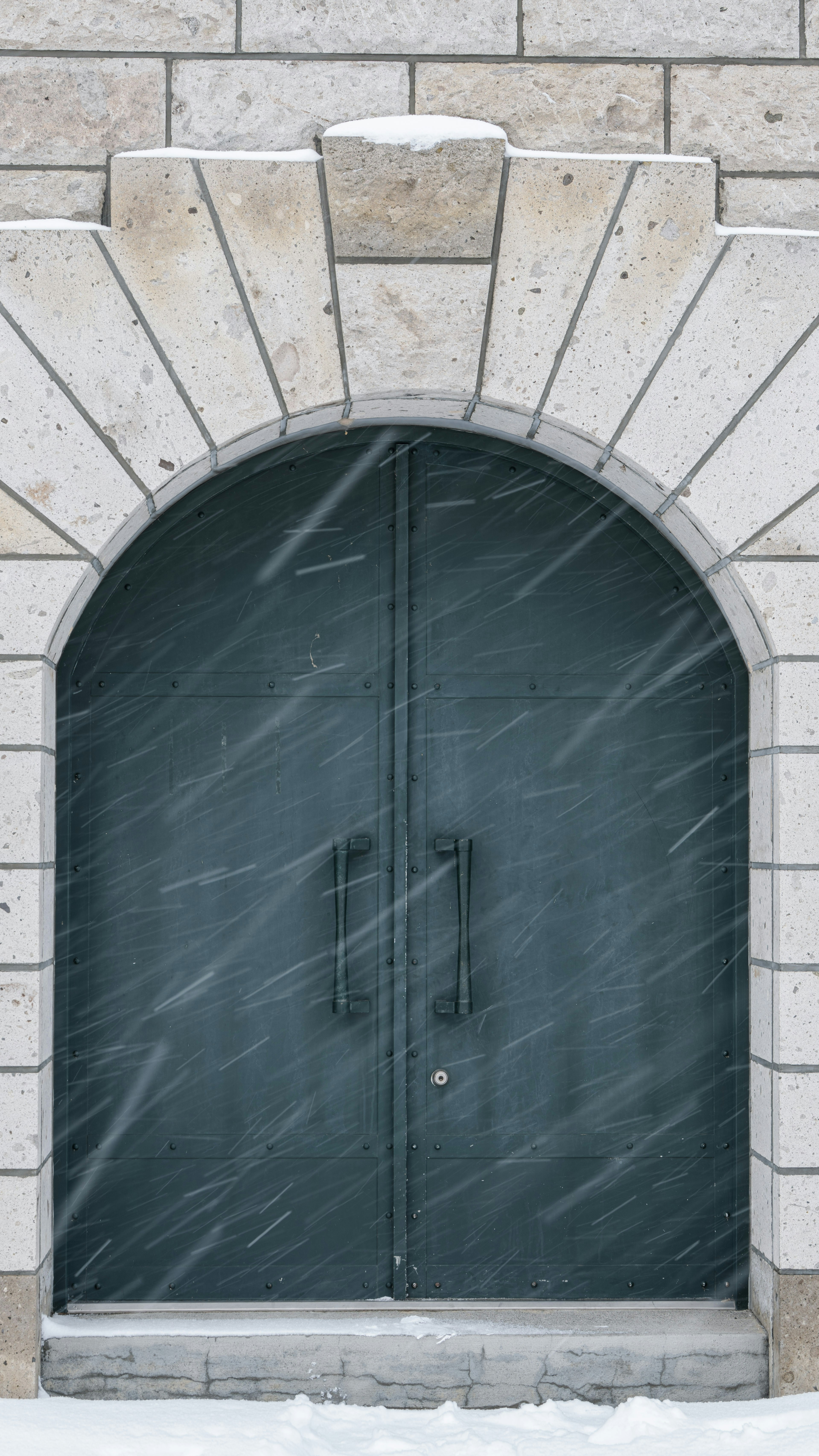 Forged in Stone: A Weathered Arch Gate Beneath Falling Snow
