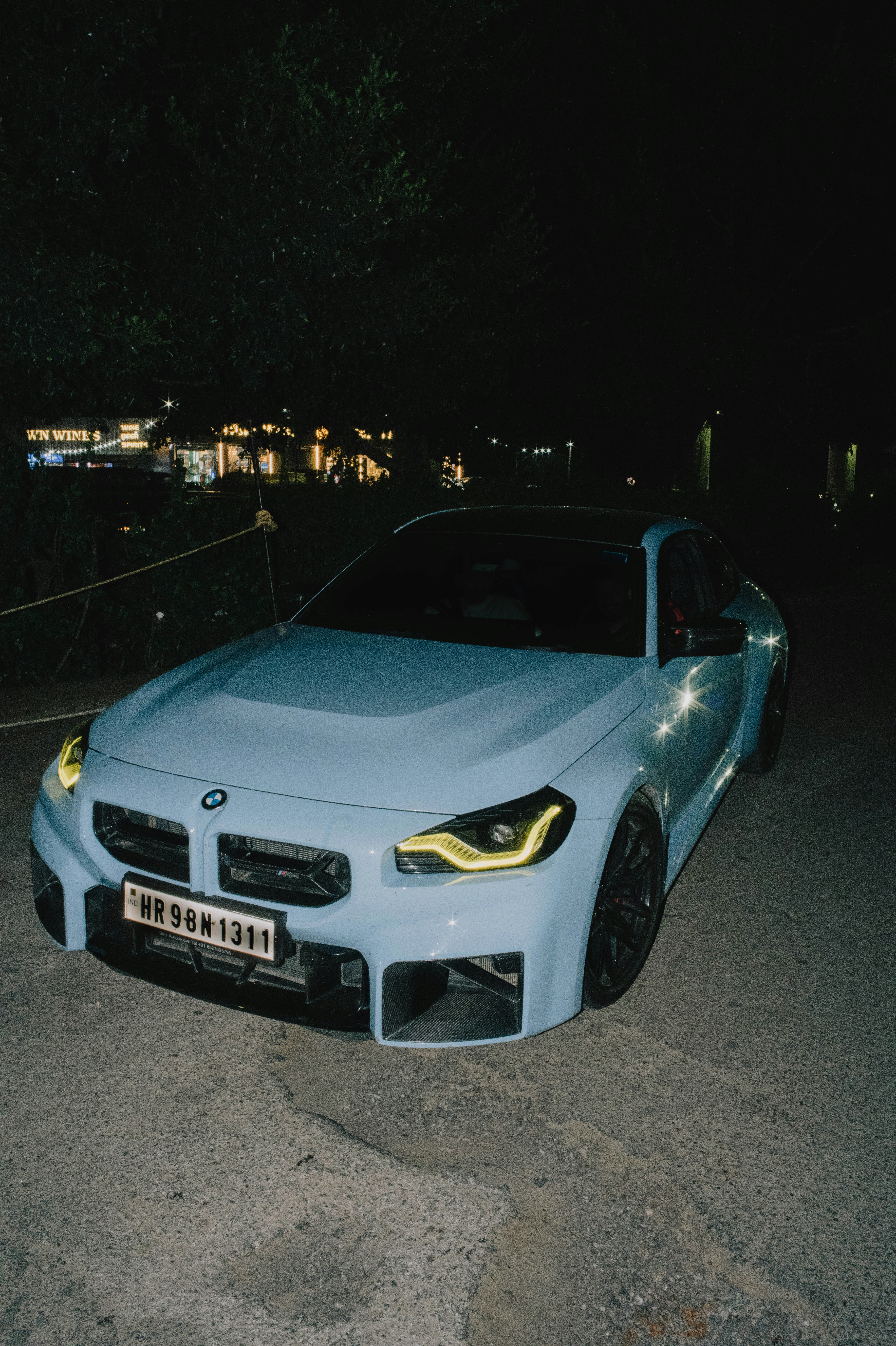 A light blue BMW parked at night
