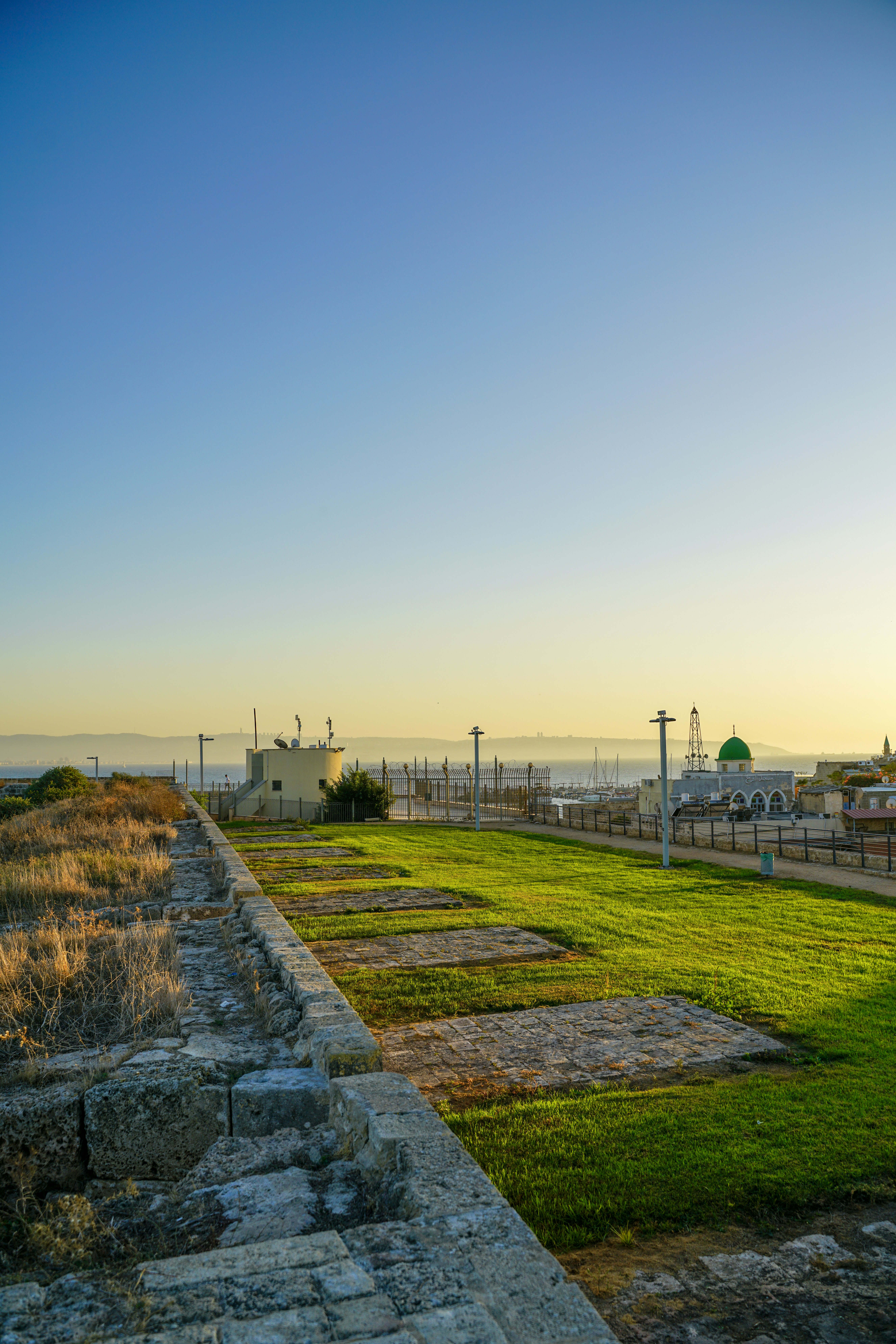 Sunlit Coastal Terrace: Green Lawn and Stone Path to the Sea