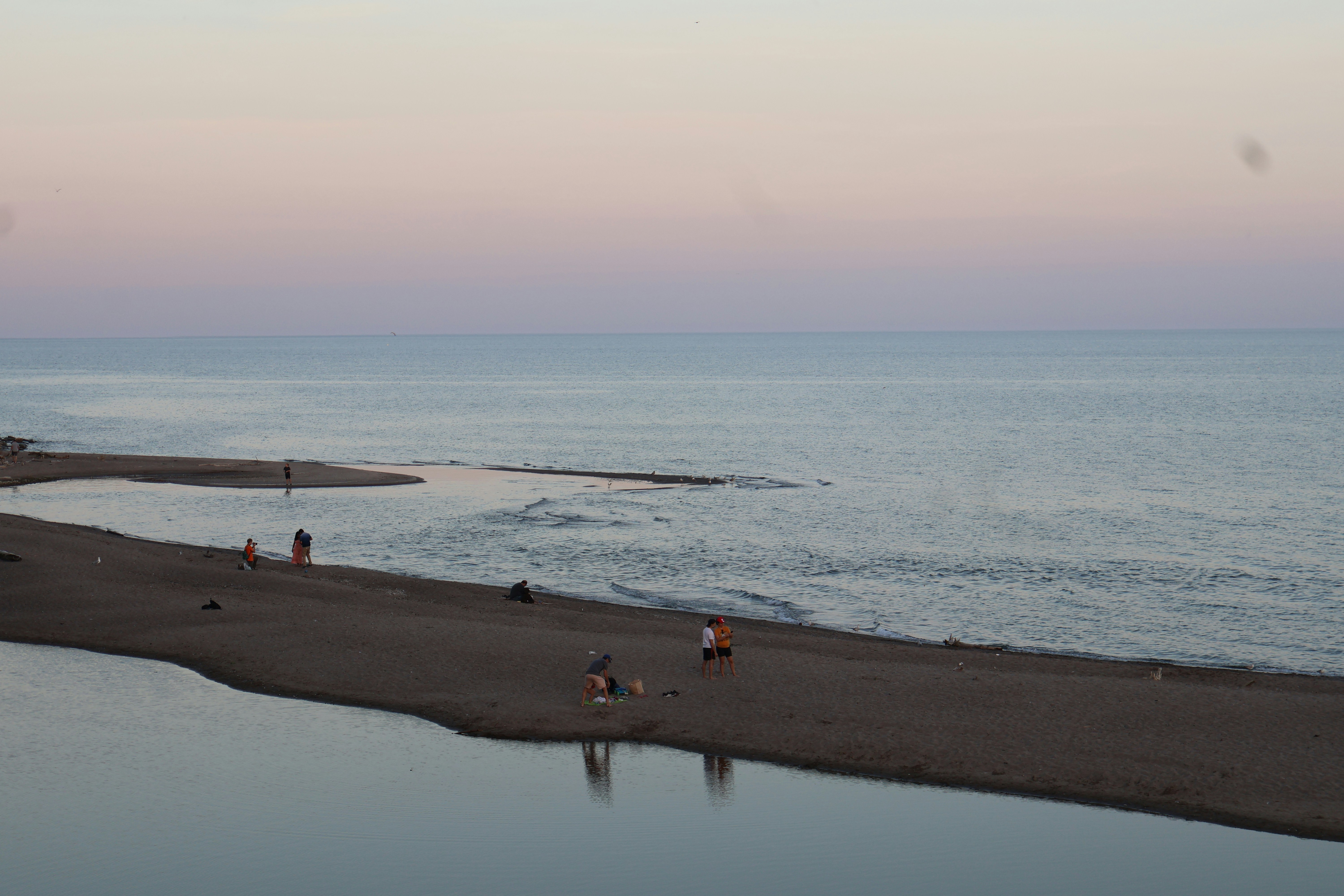Dusk on the Tidal Reach: People Silhouettes Along a Quiet Beach