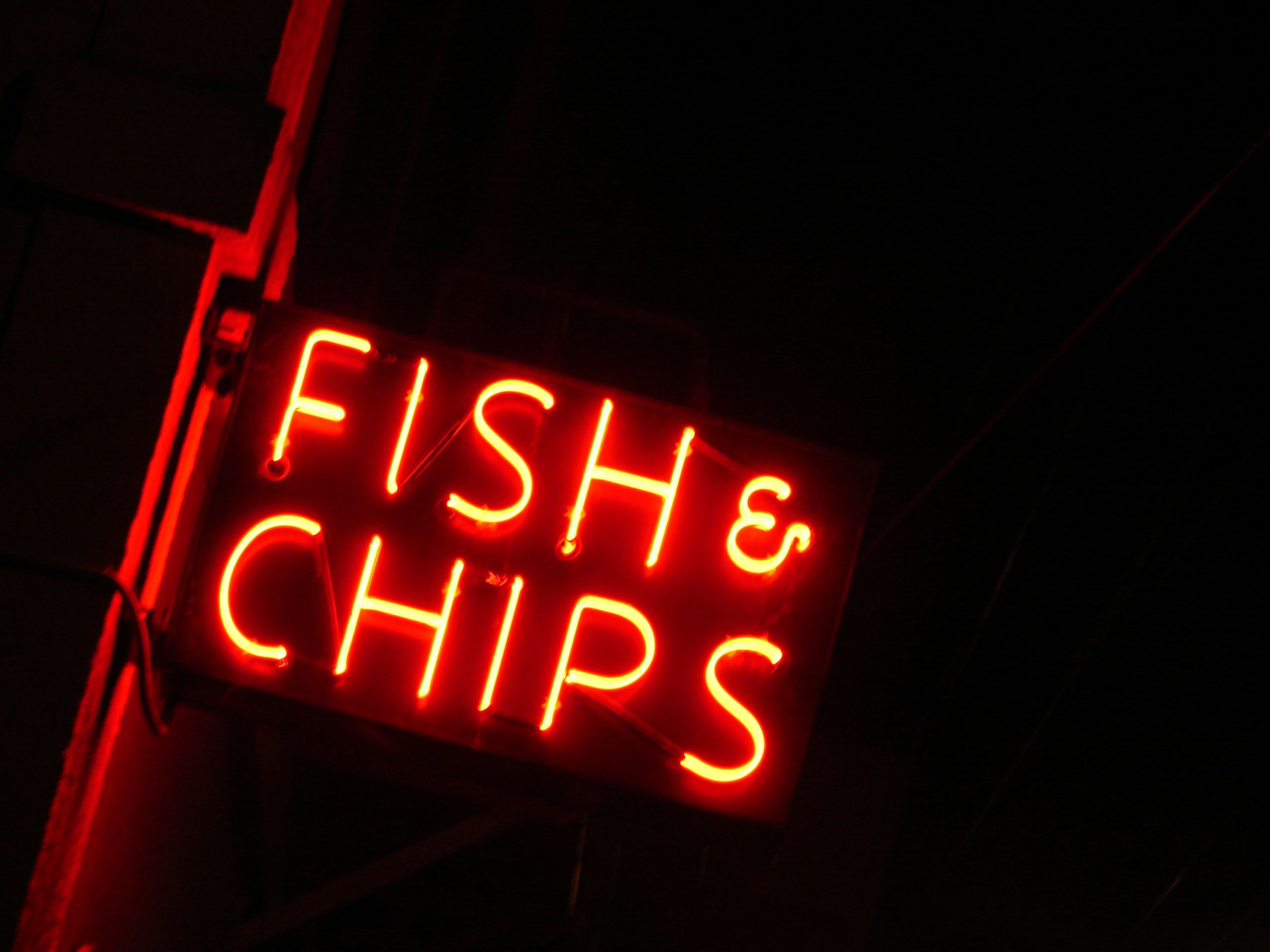 Red neon sign advertises fish and chips