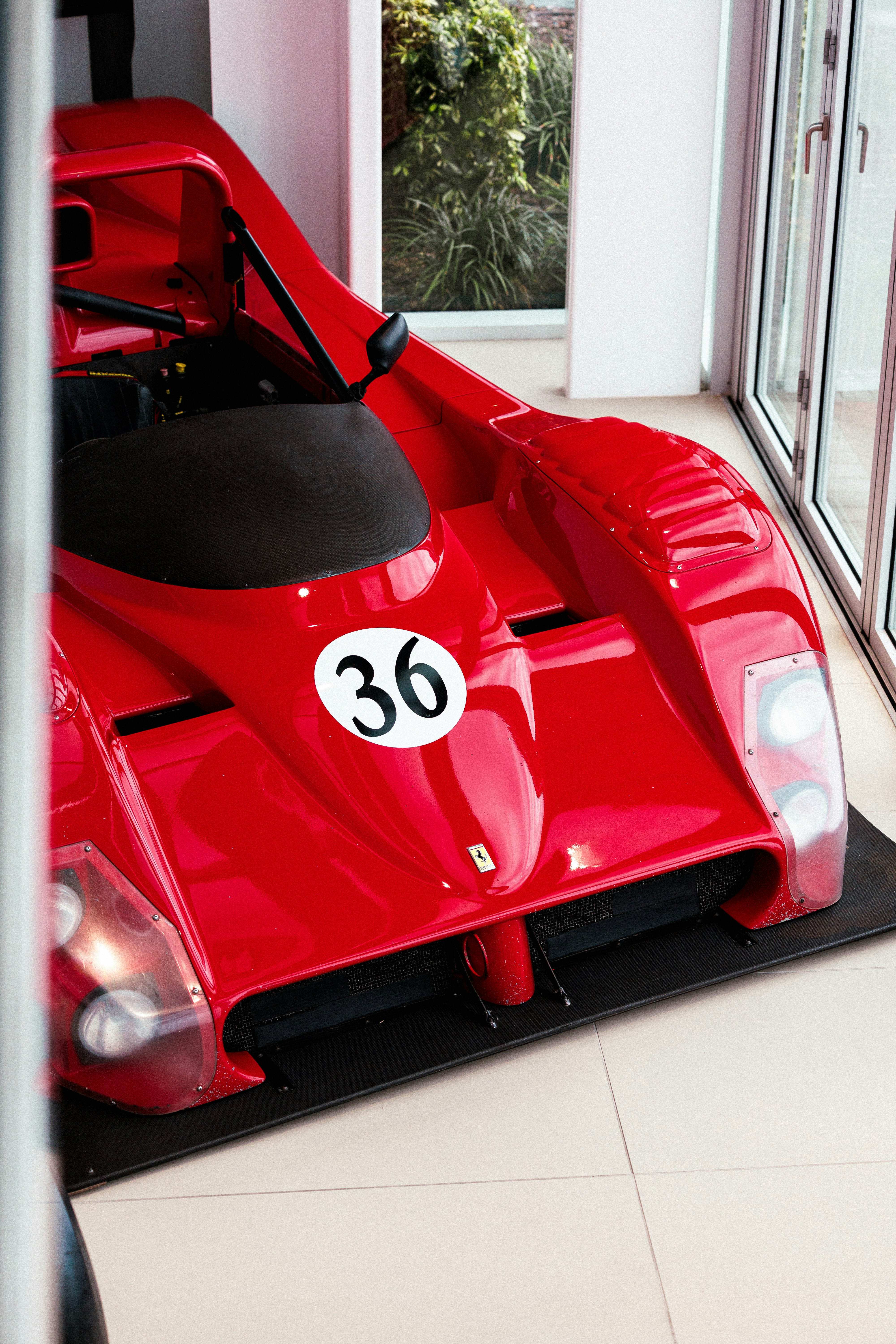 Red Racing Legend: A Classic Car Nestled by Glass and Light
