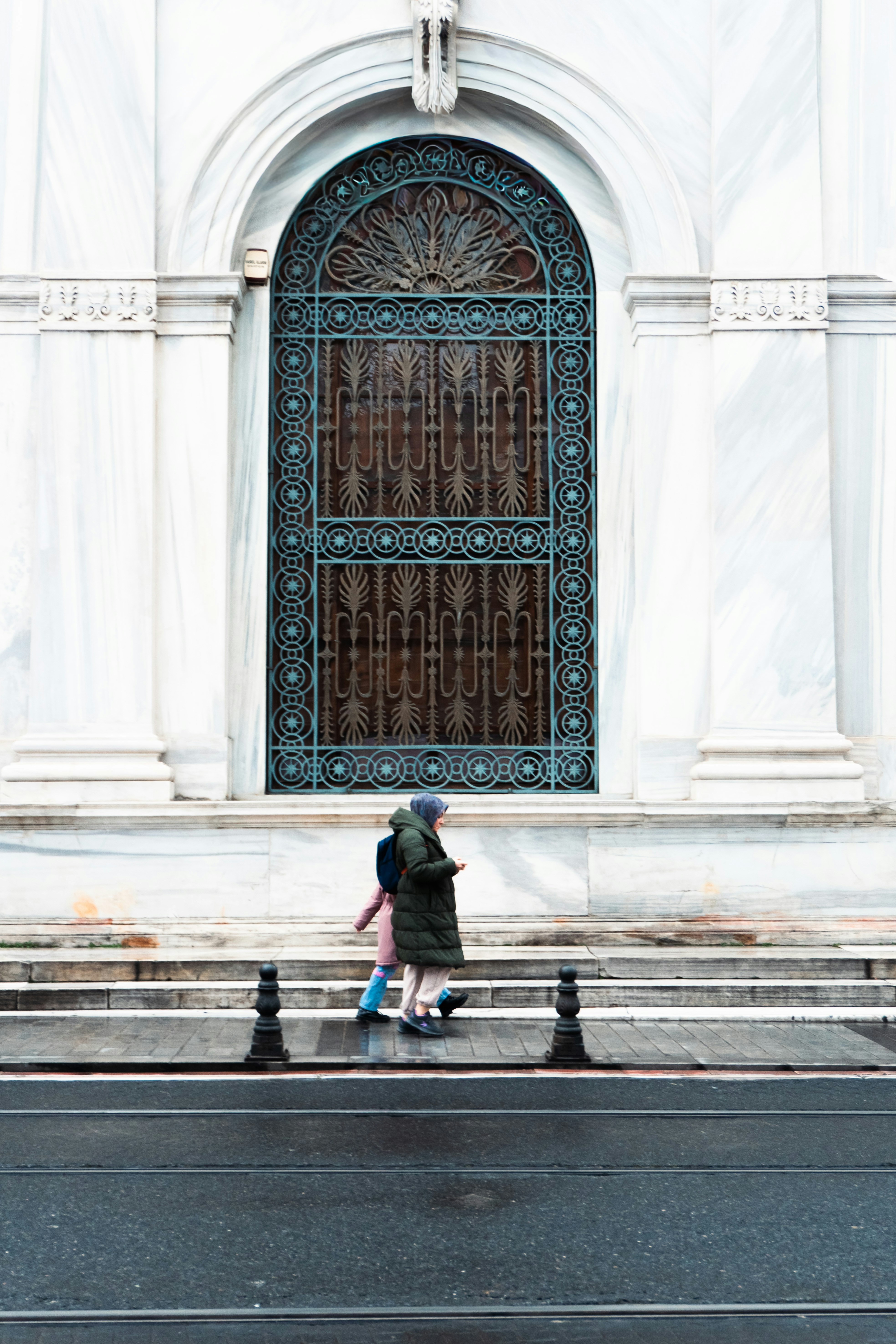 Urban Quiet: Two Wanderers Walk Past Marble Gate