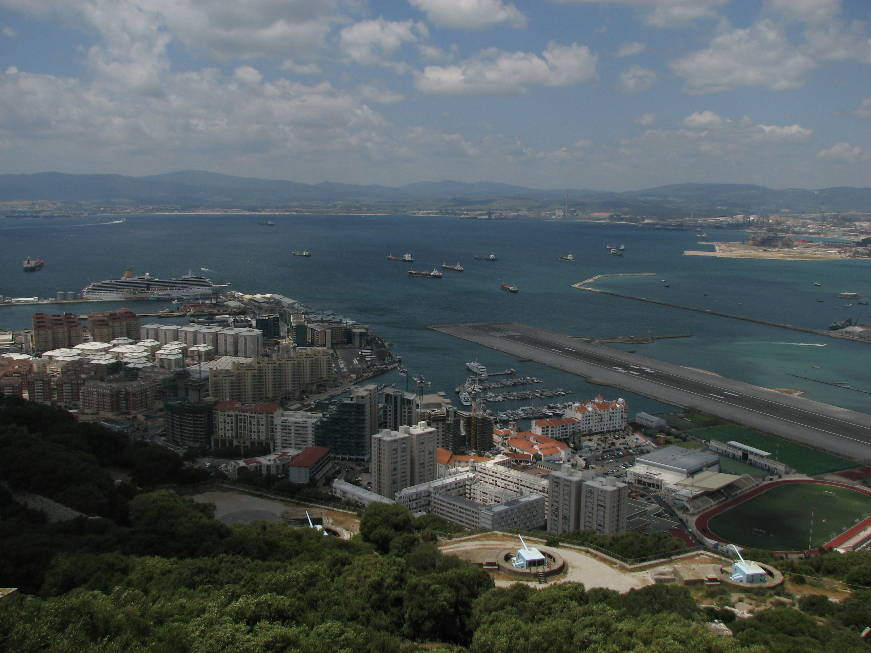 Coastal city with harbor and distant mountains under sky