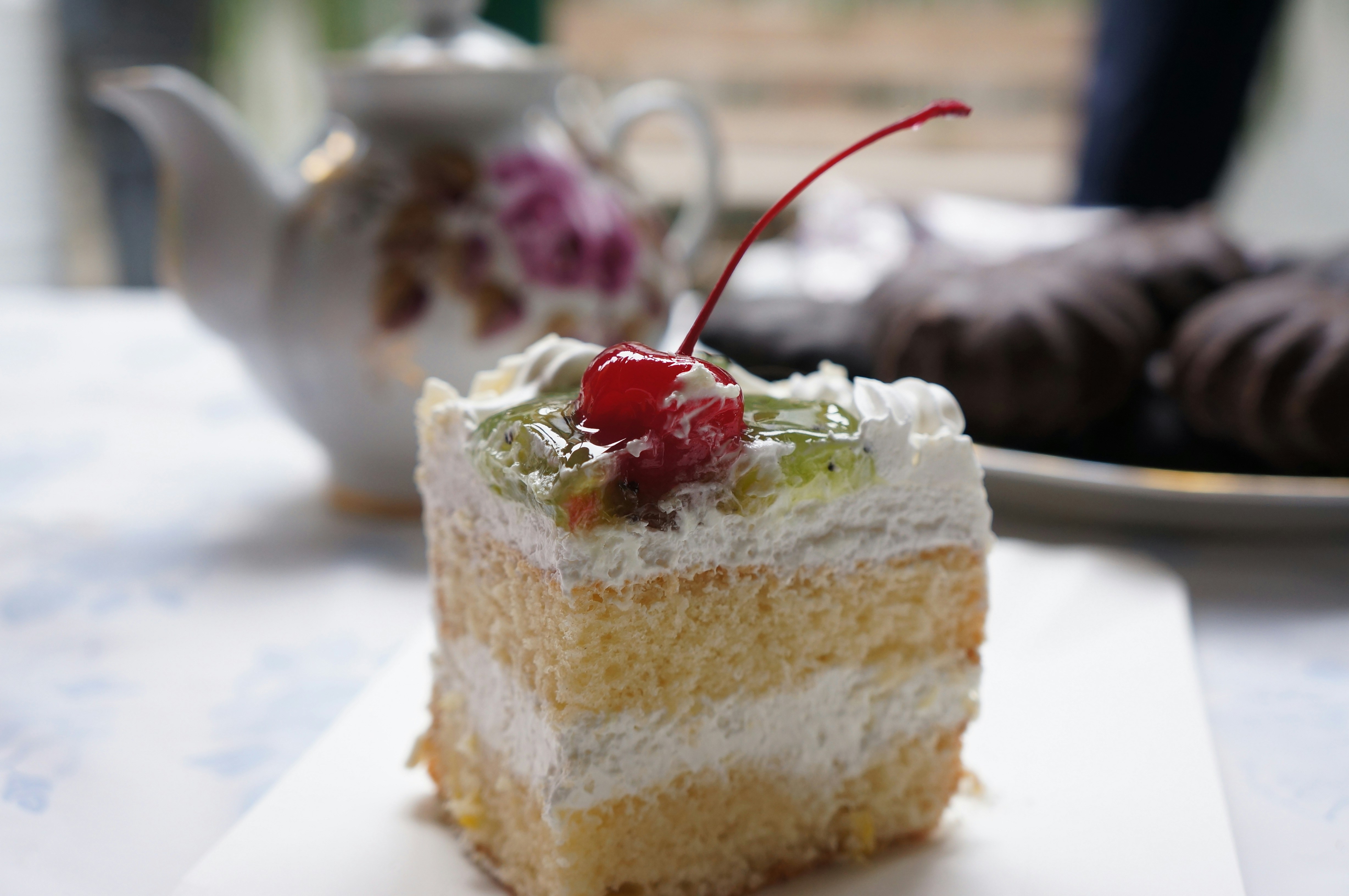 Sugared Slice: A Cherry-topped Layered Cake on a Subtle Dessert Spread