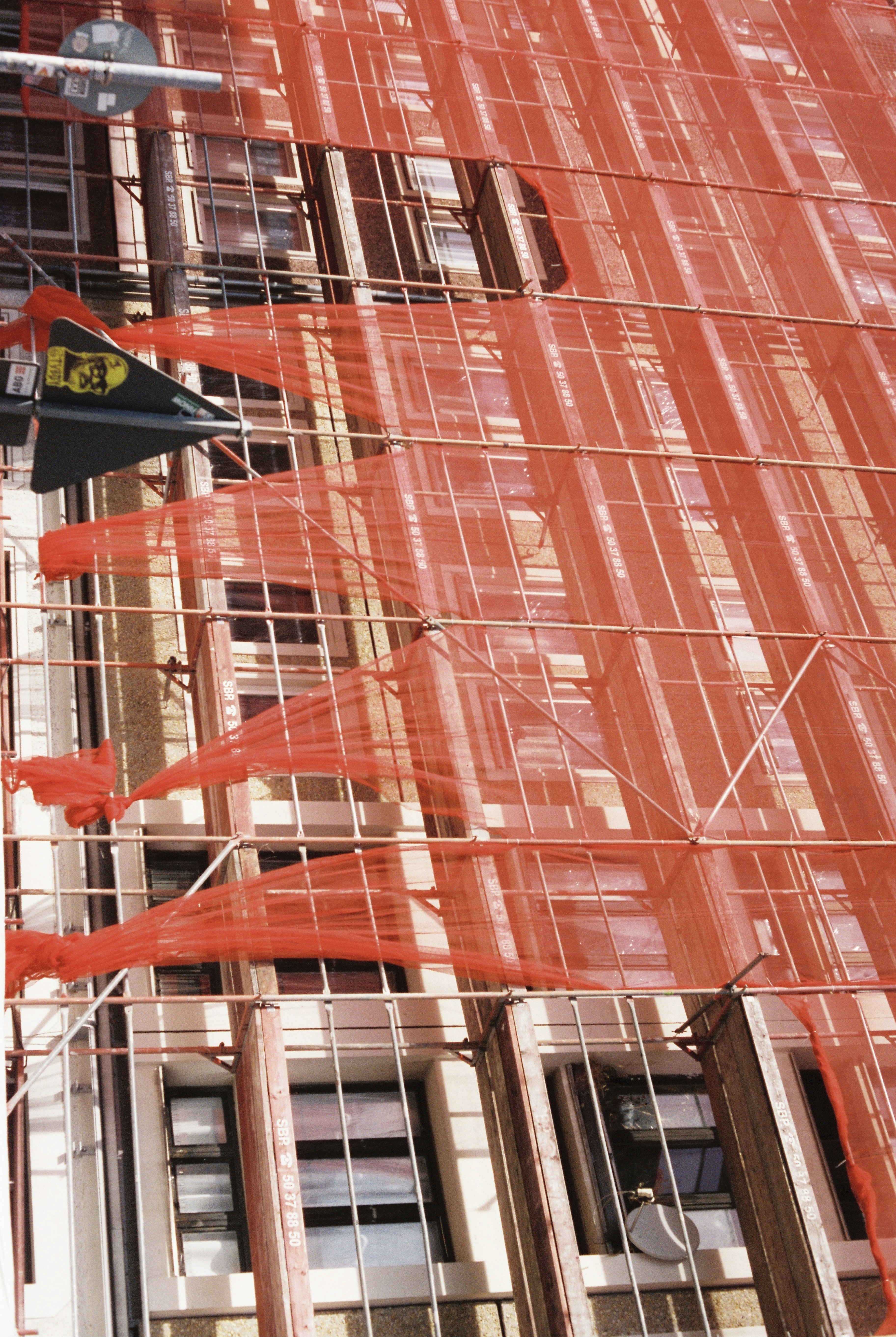 Red Mesh over Urban Facade: A Curtain of Color on a City Building